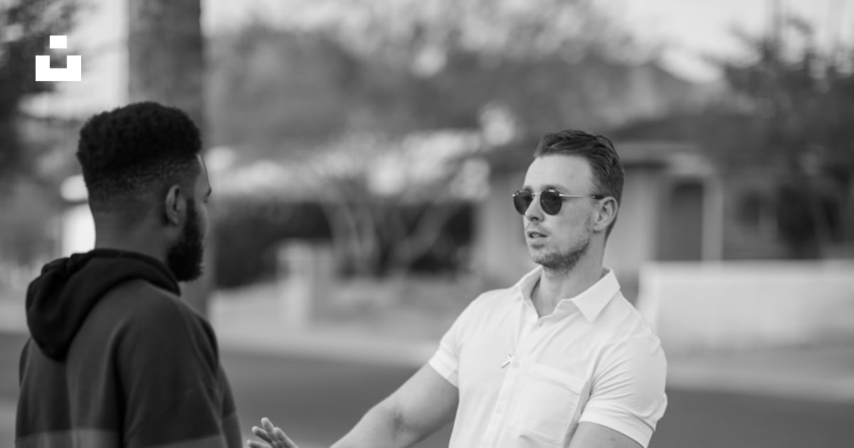 Man In White Dress Shirt And Black Pants Standing Beside Man In Black