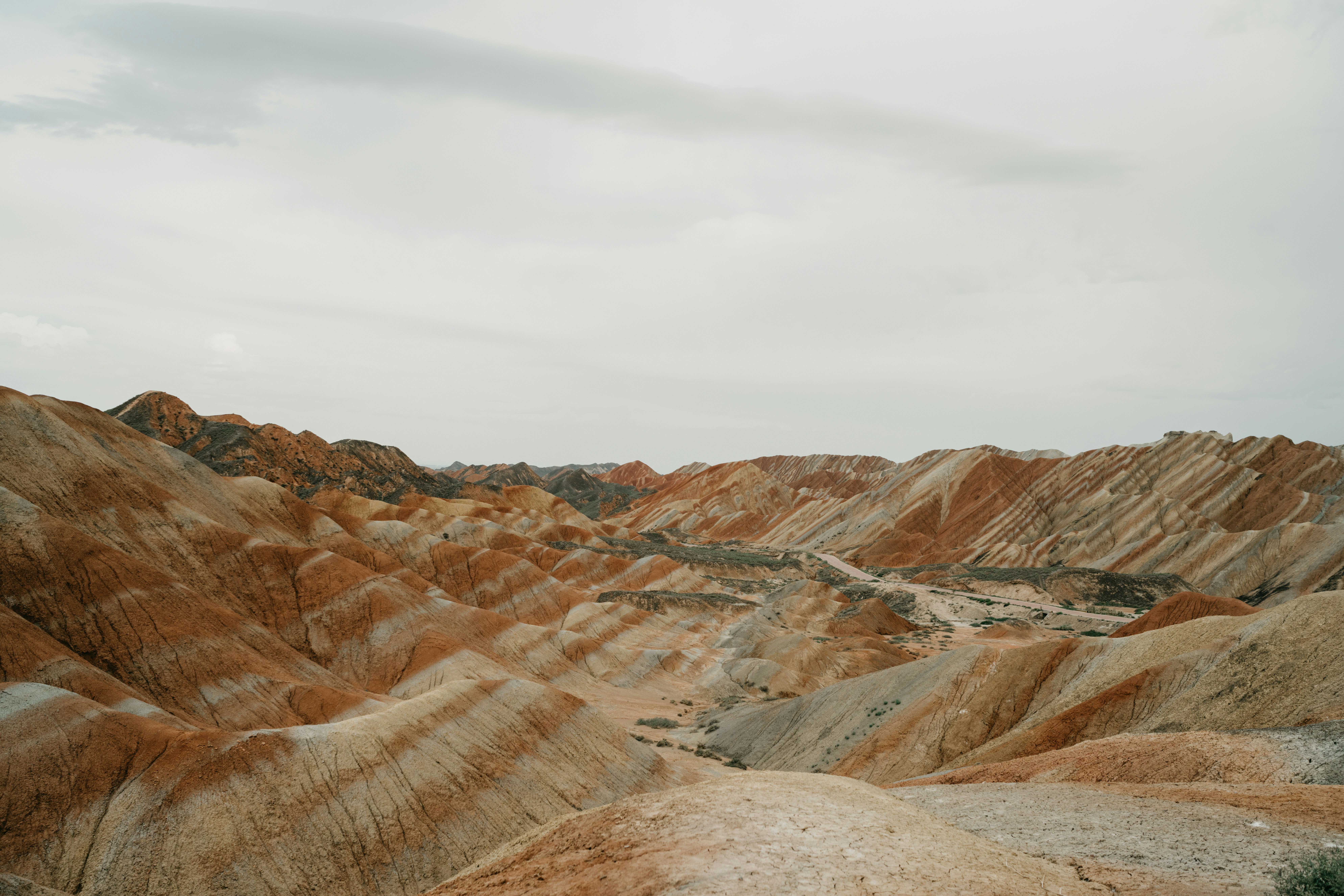 Vibrant, undulating hills display a spectrum of earthy tones in a remote landscape. The geological formations reflect the passage of time and natural processes.