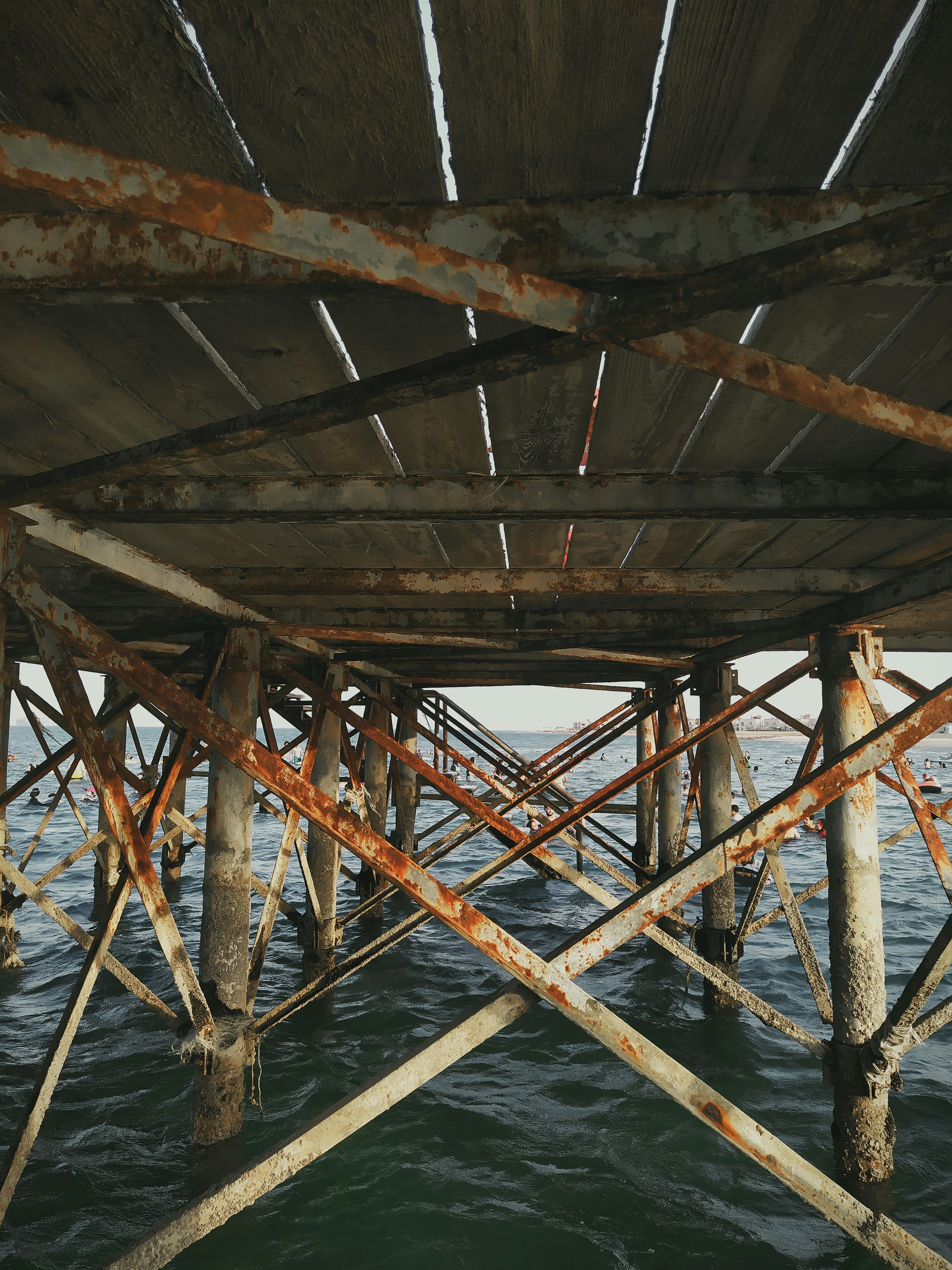 Underneath the Pier: Rusted Trusses Converge Toward the Sea
