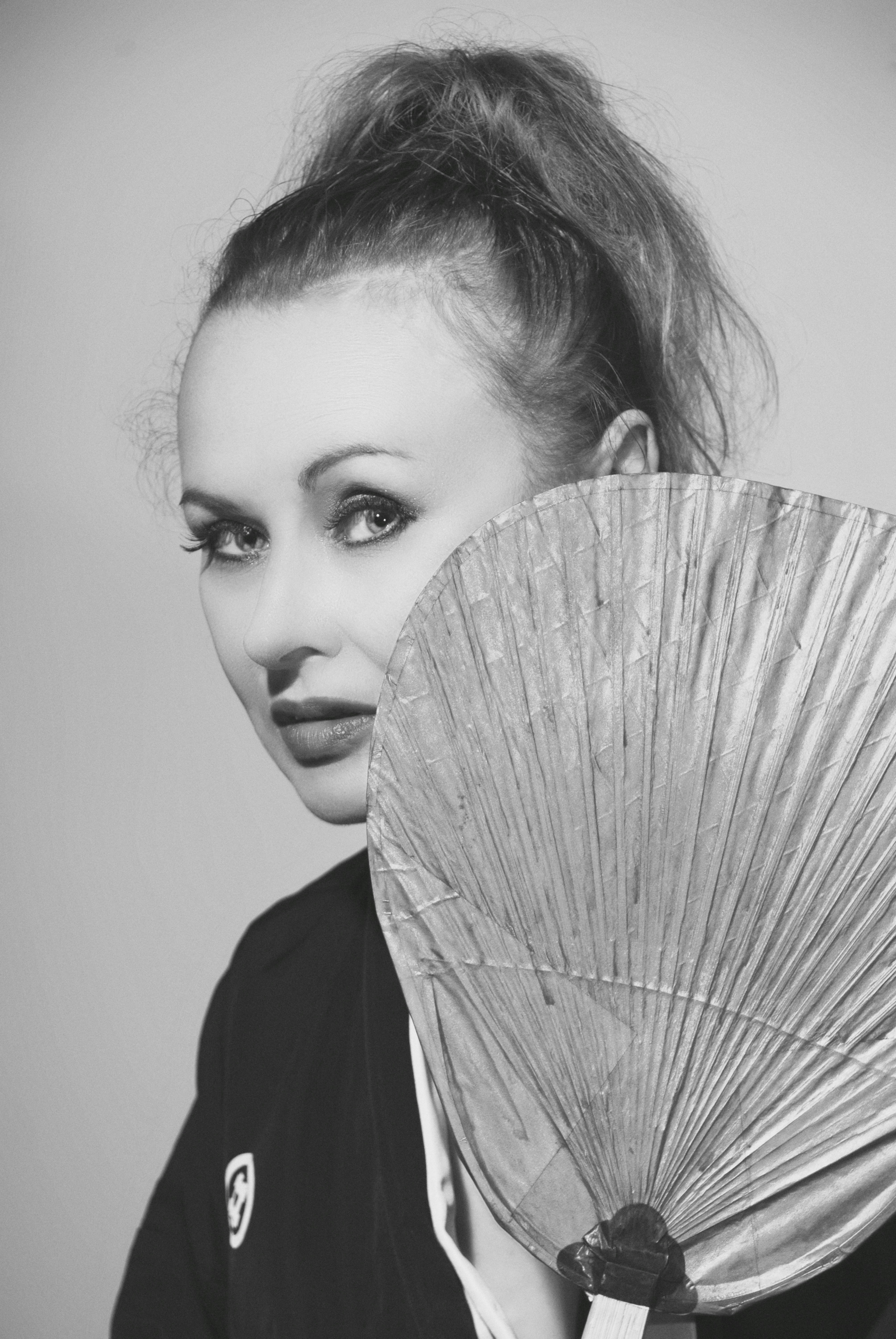 Centered Gaze Behind a Fan: A Monochrome Portrait with Subtle Mystery