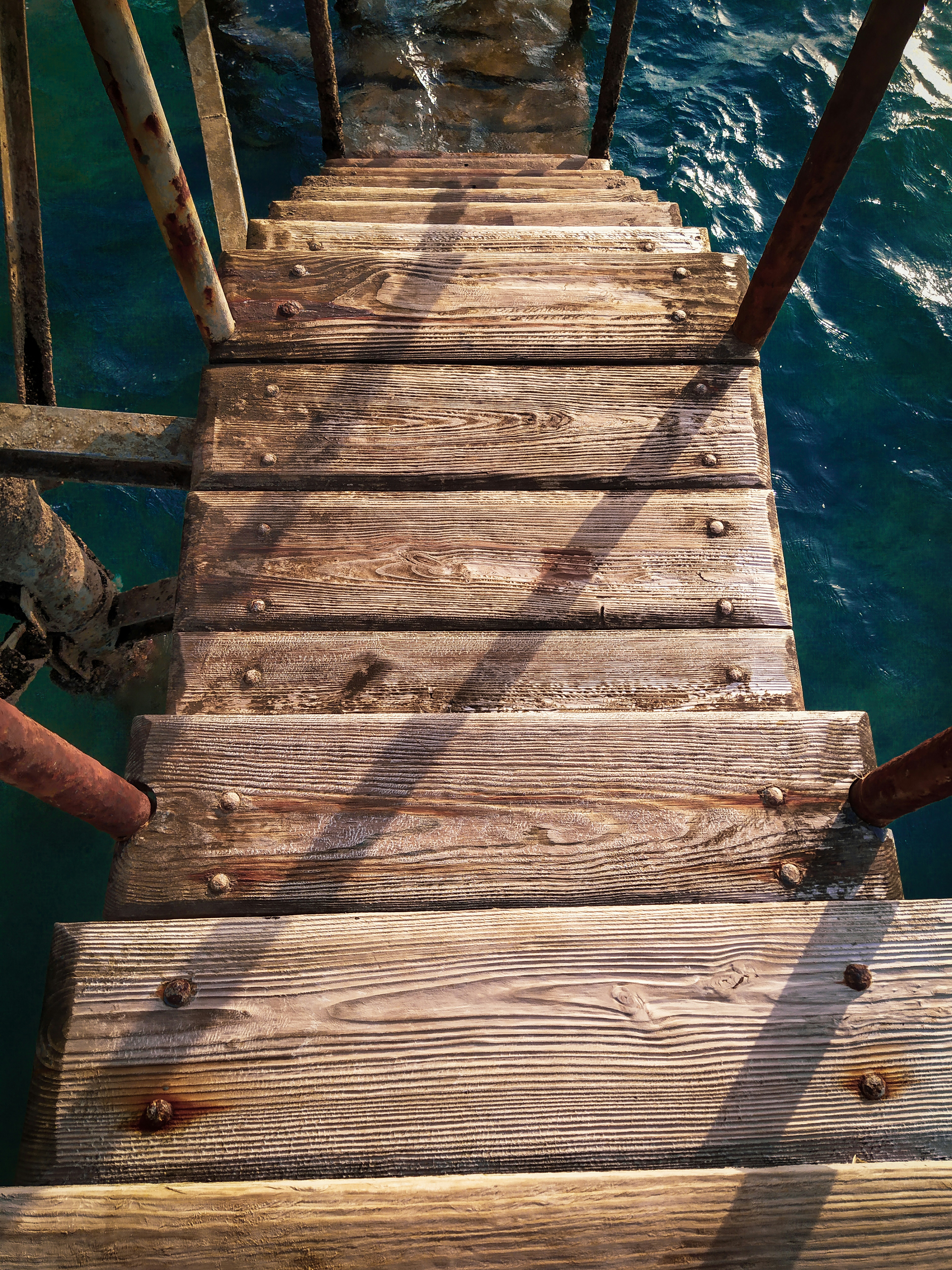 brown wooden dock over blue water photo – Free Staircase Image on Unsplash