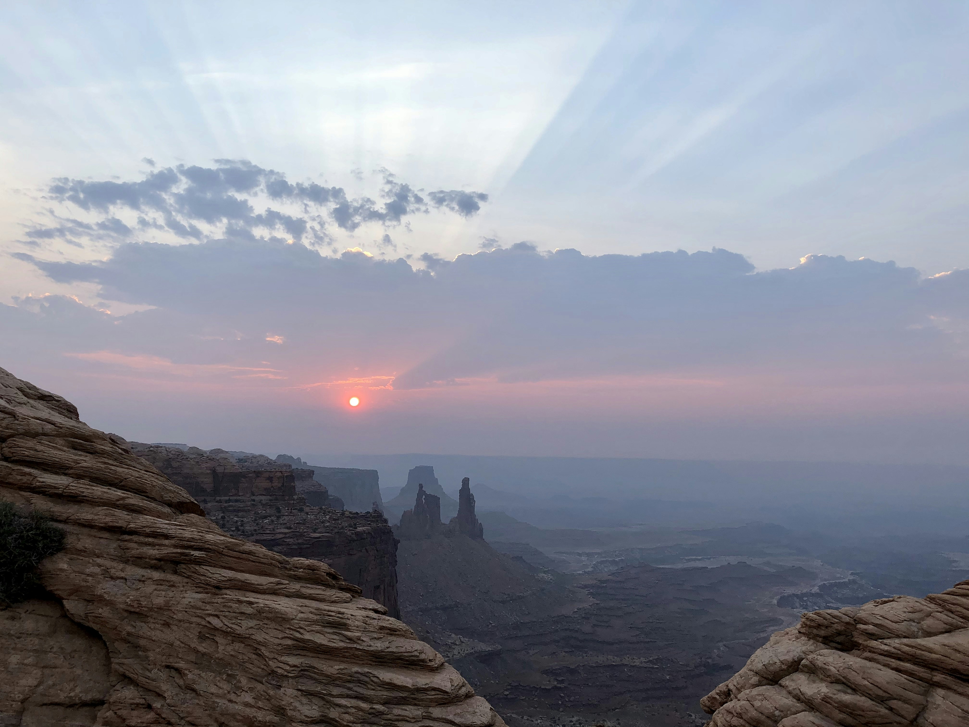 Dawn on the Layered Canyon Rim: Sun Pierces the Distant Buttes