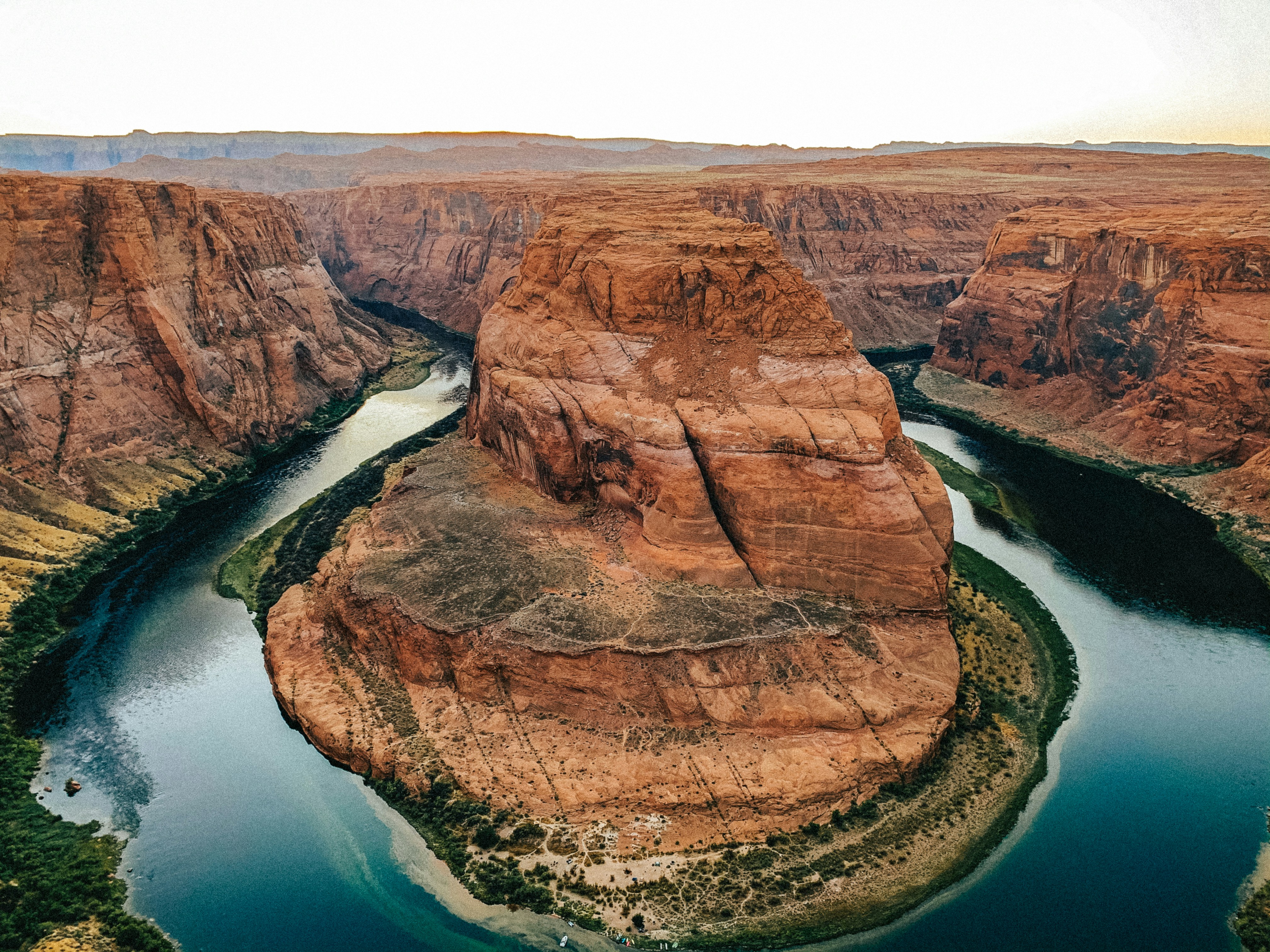 Majestic rock formation surrounded by the winding Colorado River, showcasing the intricate patterns of erosion. Aerial view highlights the natural beauty of the landscape.