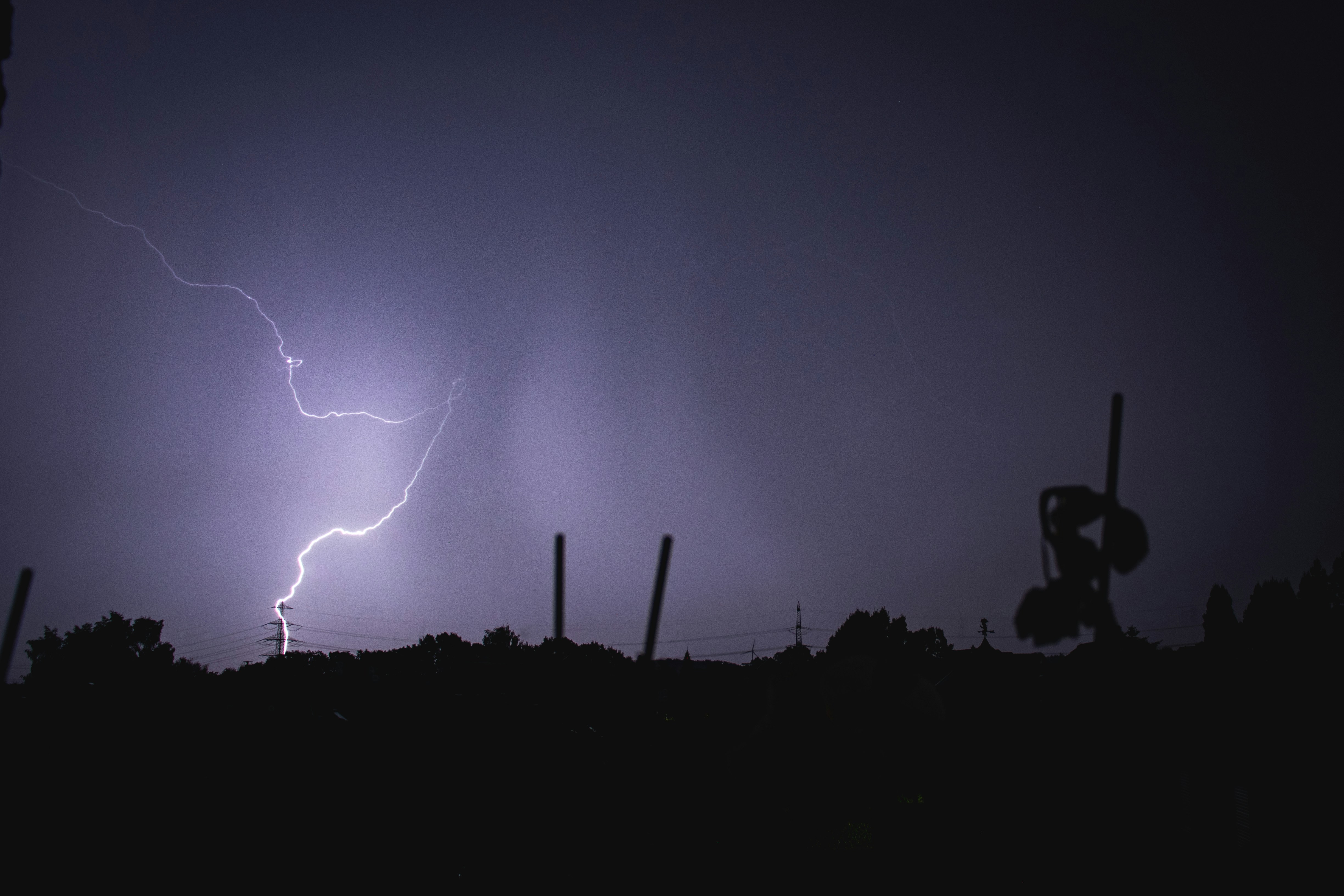 A lightning bolt illuminates the darkened landscape, creating a dramatic contrast against the stormy sky.