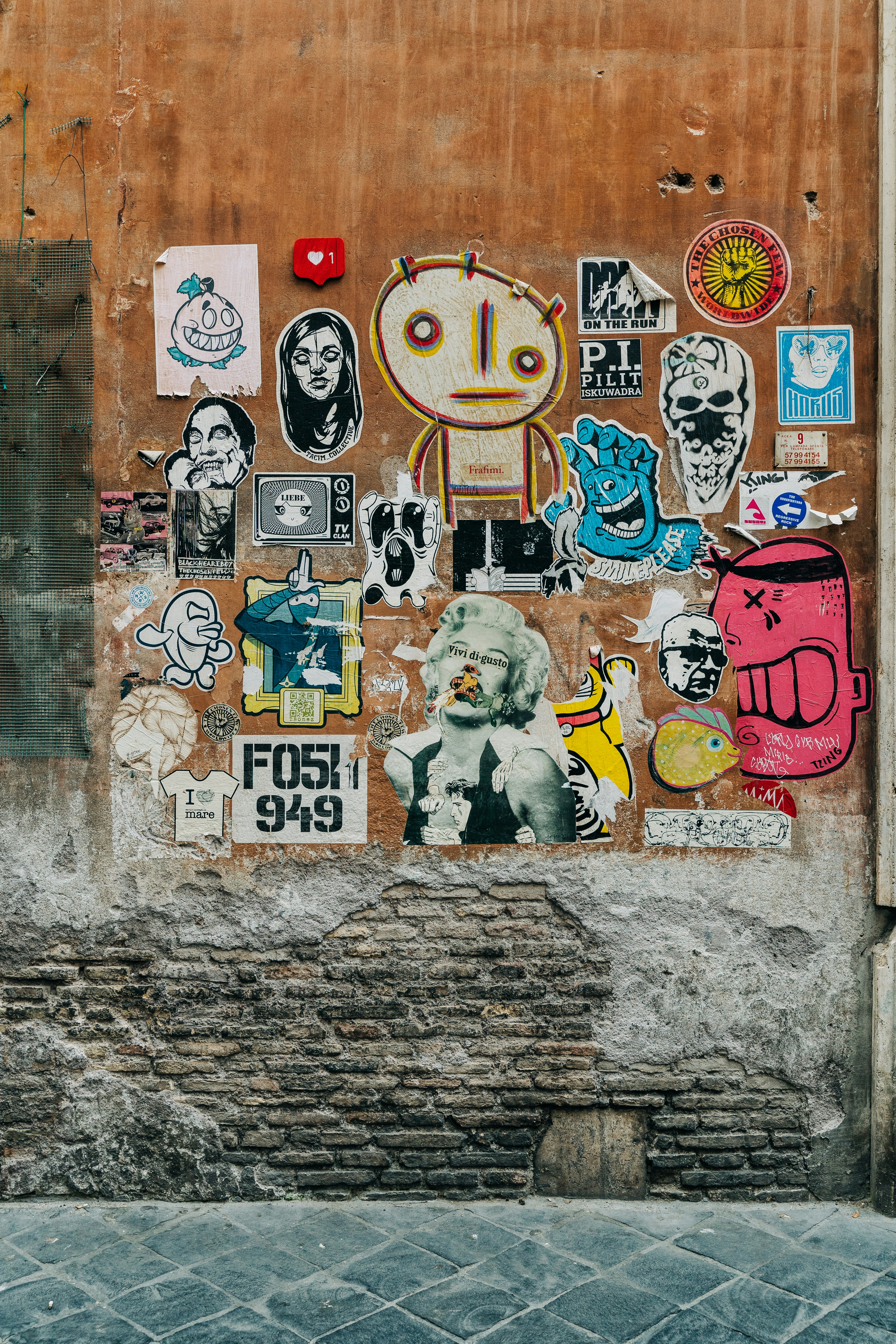 Different wall textures with stickers forming a colorful mural in downtown Rome. | red white and black wall art