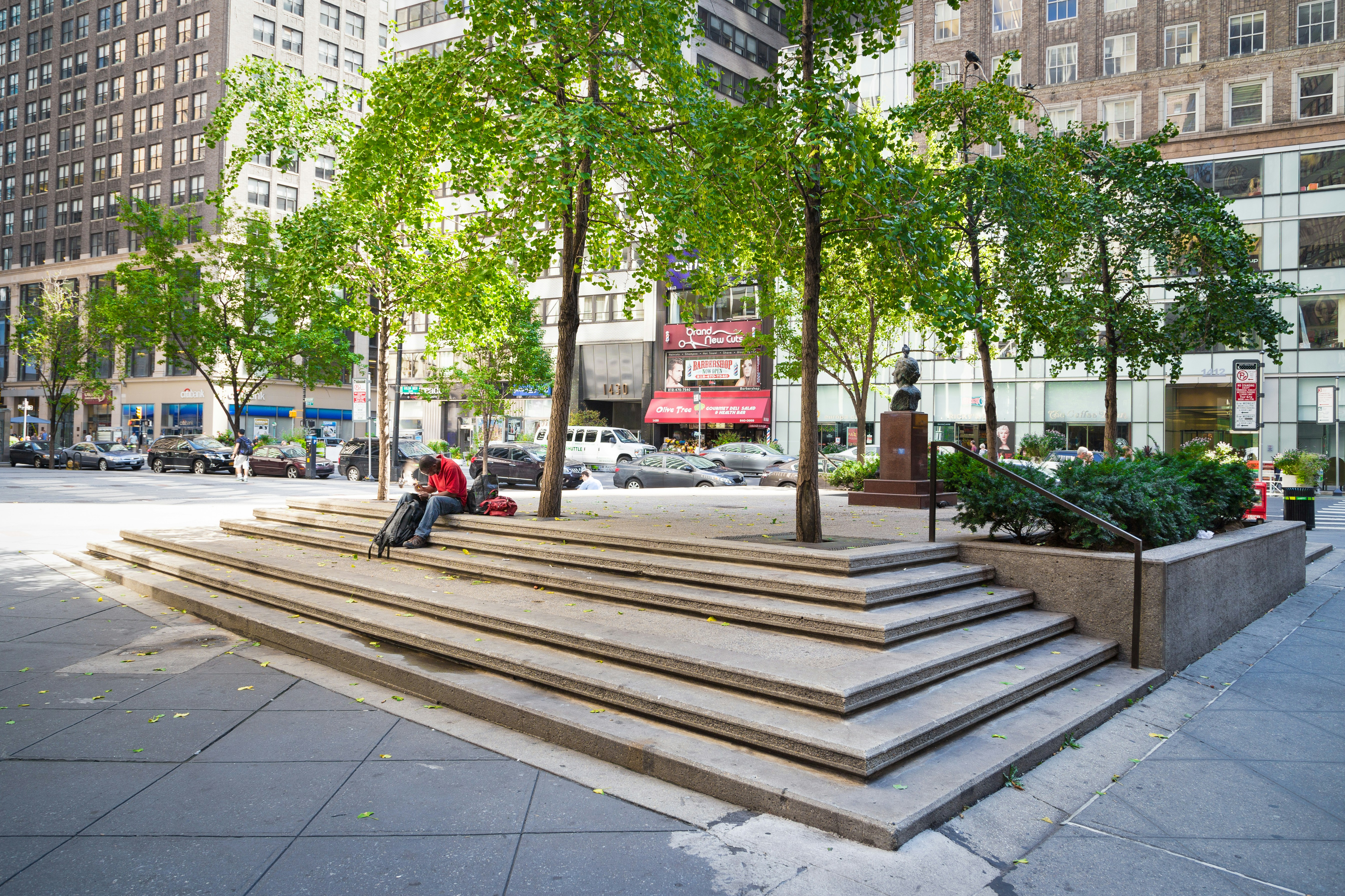 man in red jacket sitting on brown wooden bench during daytime