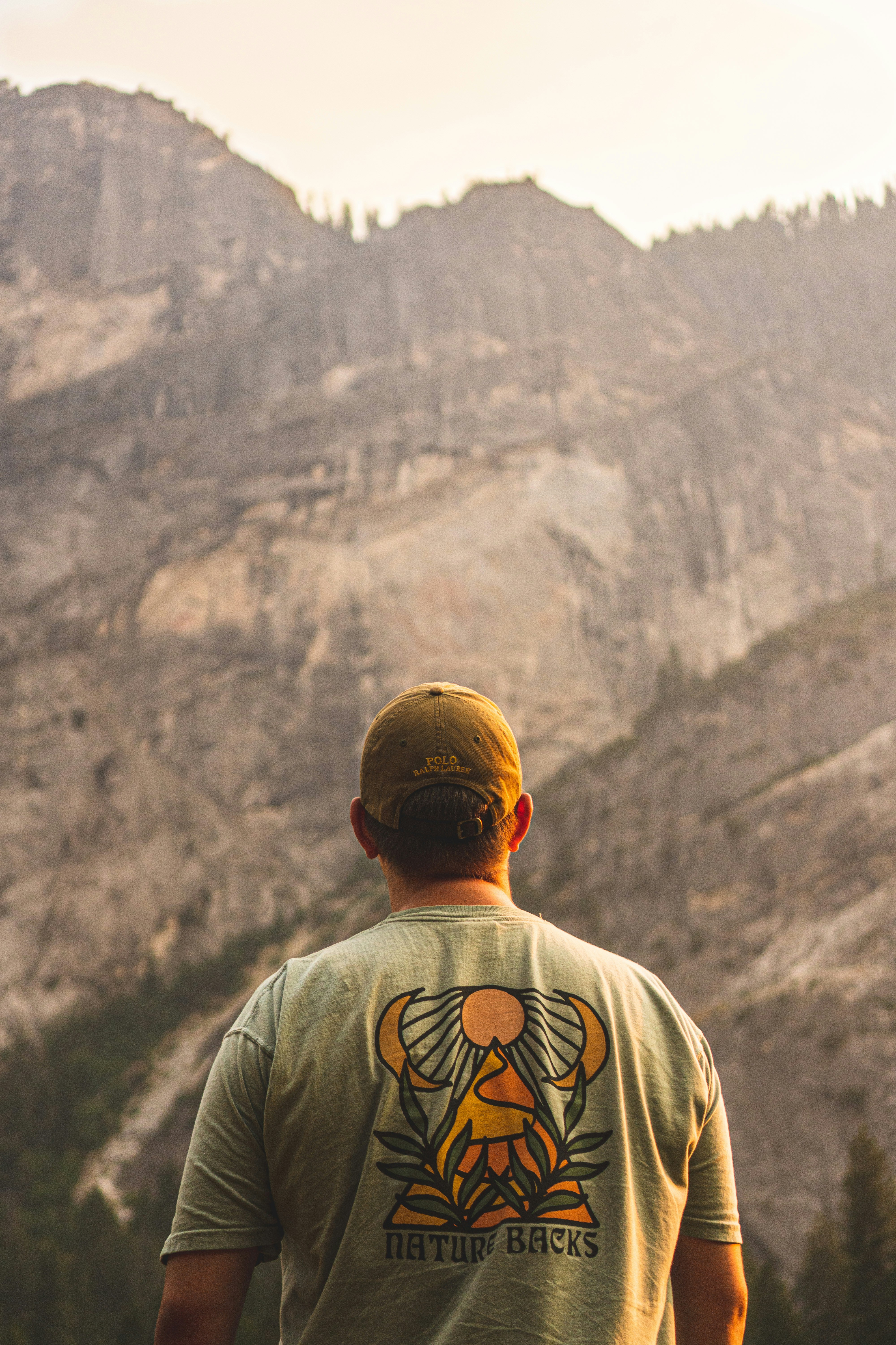 Back-turned hiker frames ancient granite cliffs at sunset
