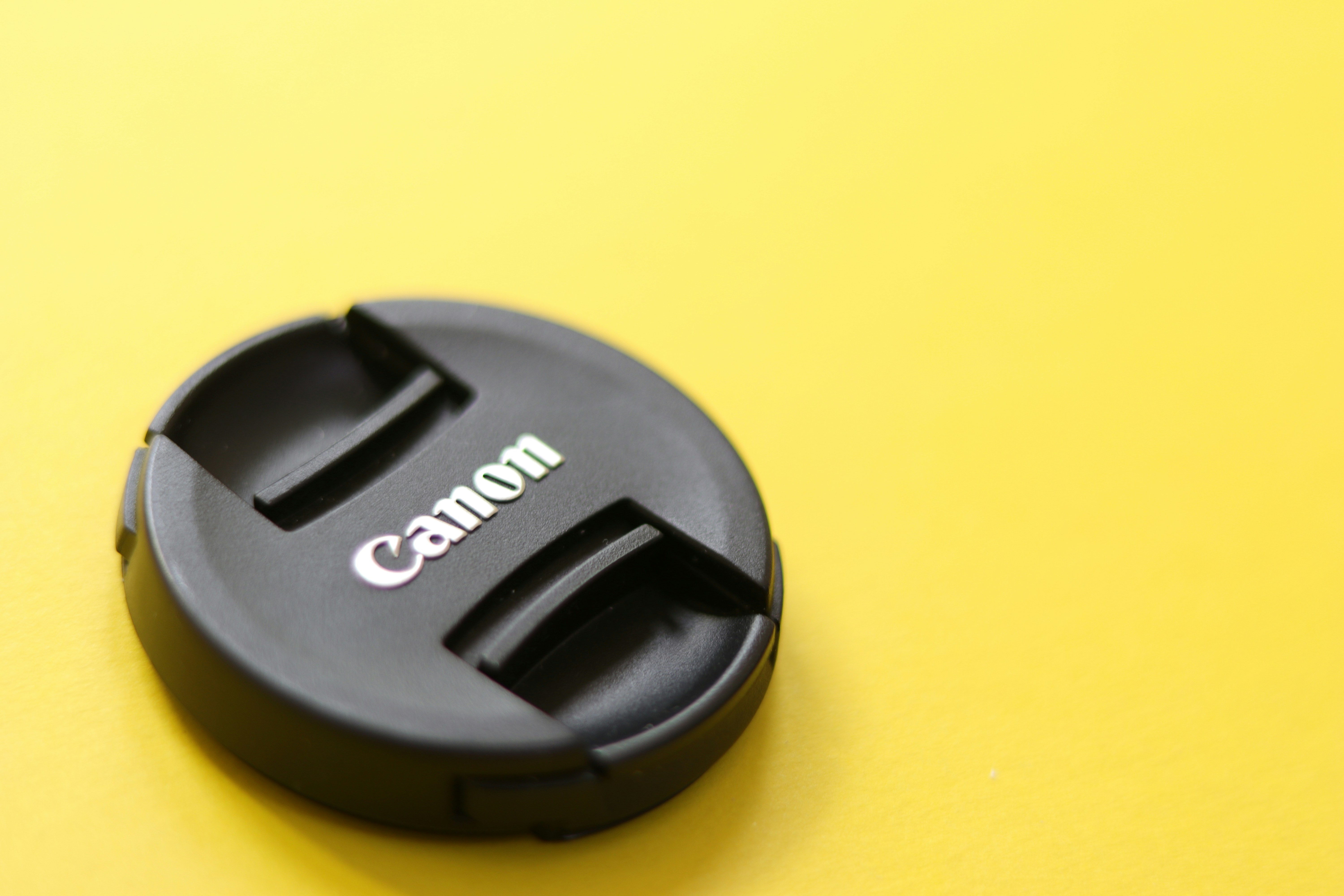 Canon Lens Cap on a Bold Yellow Studio Surface