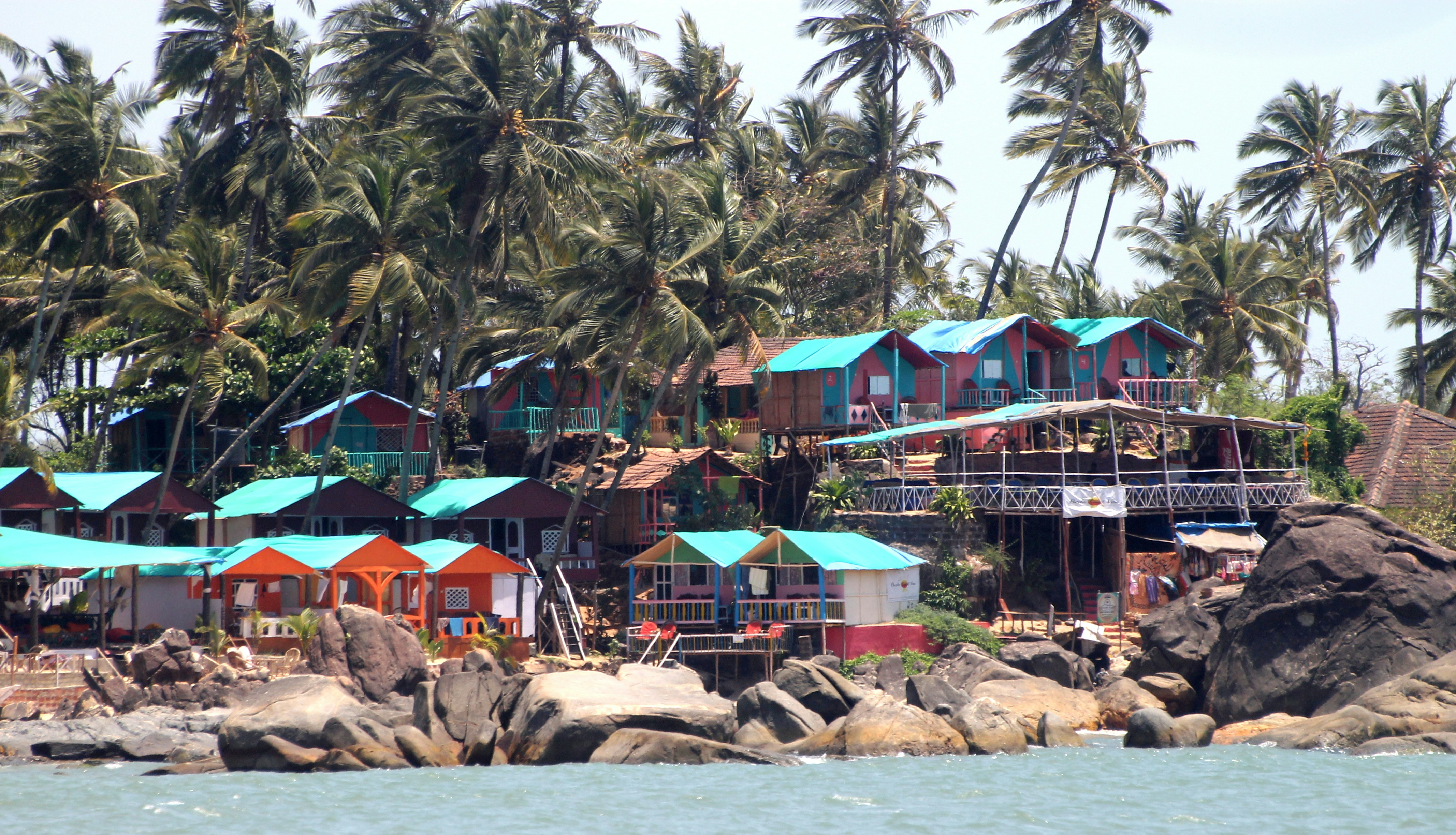 Colorful seaside villas fringe a rocky shoreline under swaying palms