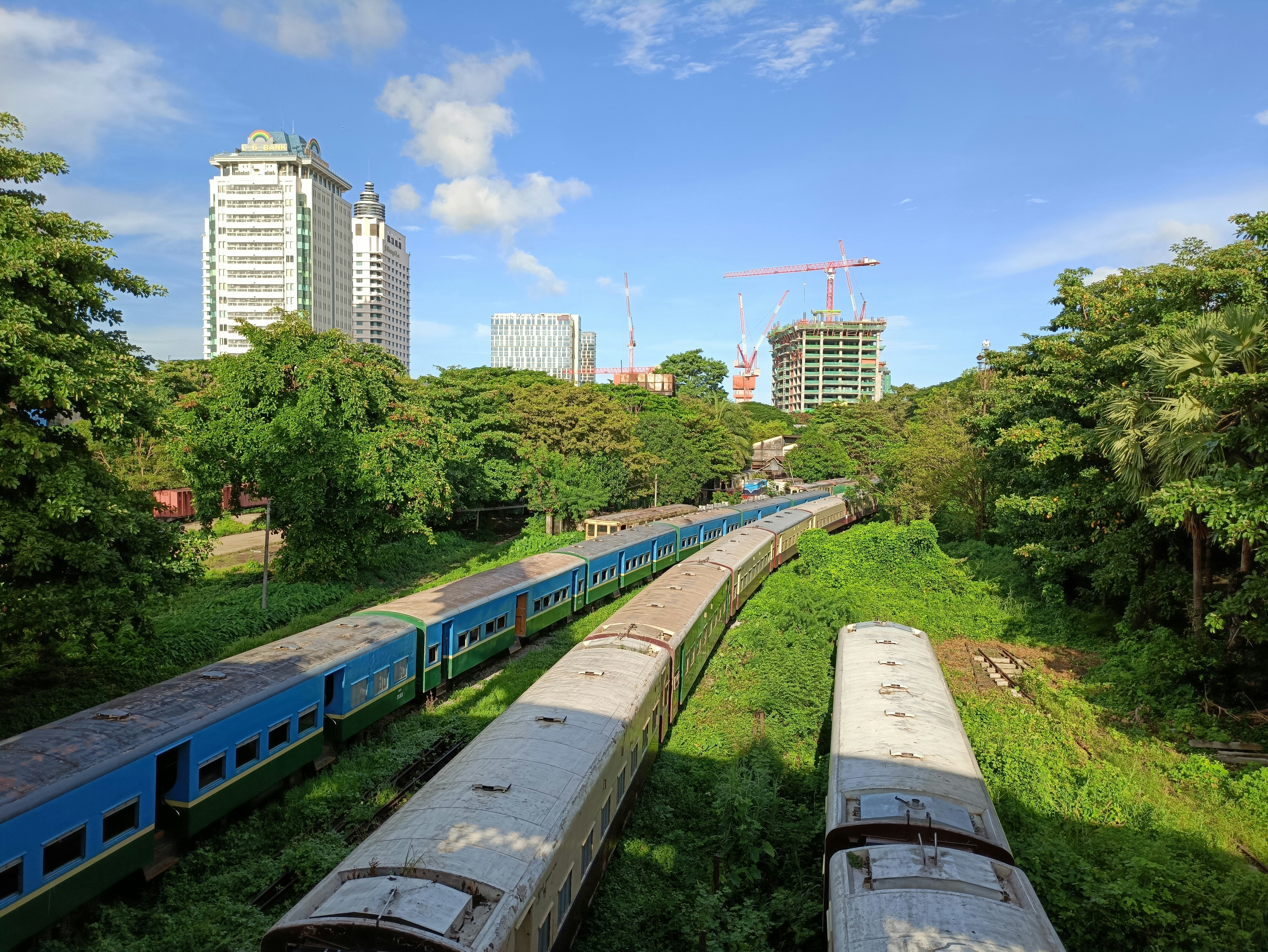 gray and brown train rail near green trees and high rise buildings during daytime
