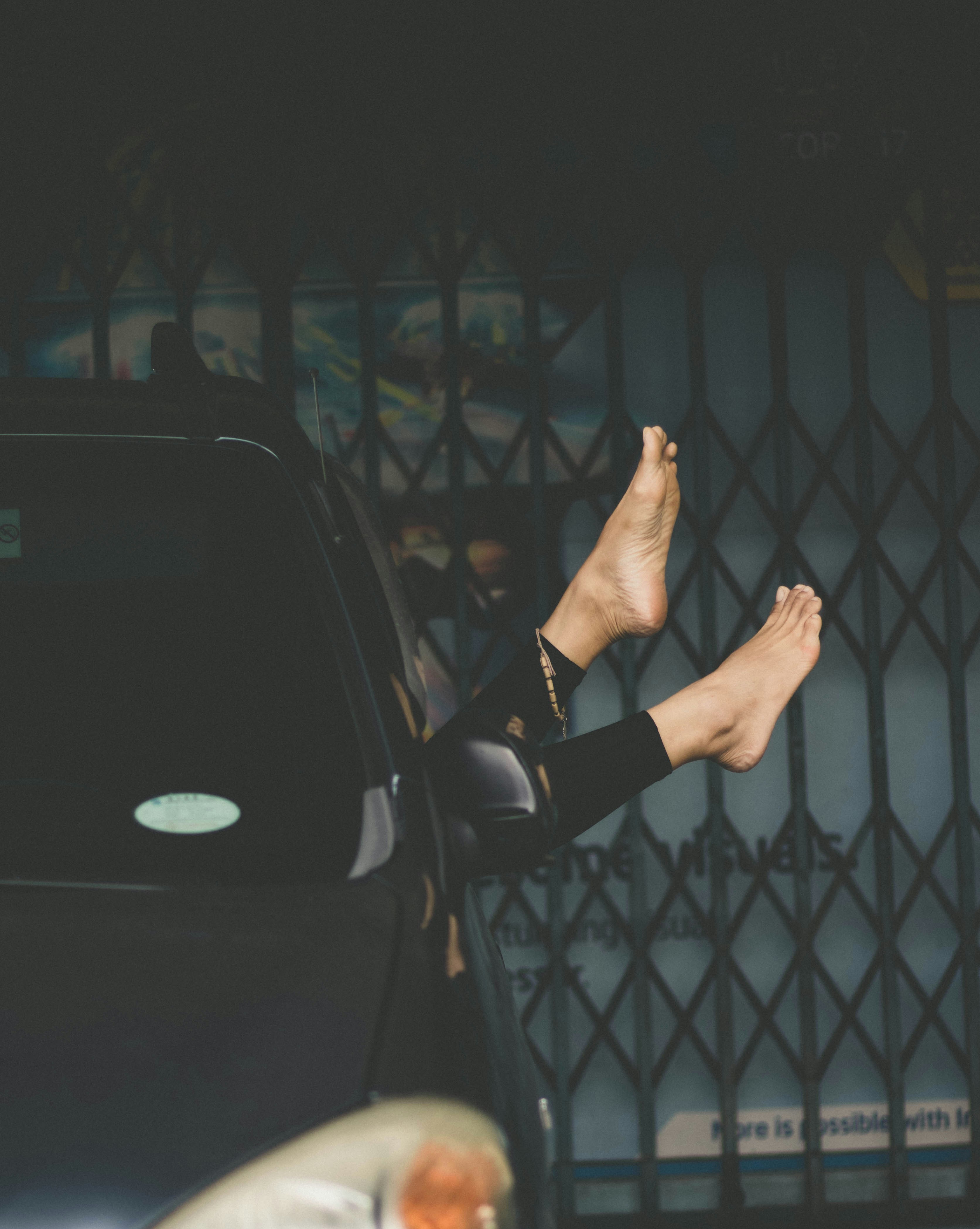 person in black pants and black leather shoes standing beside black car