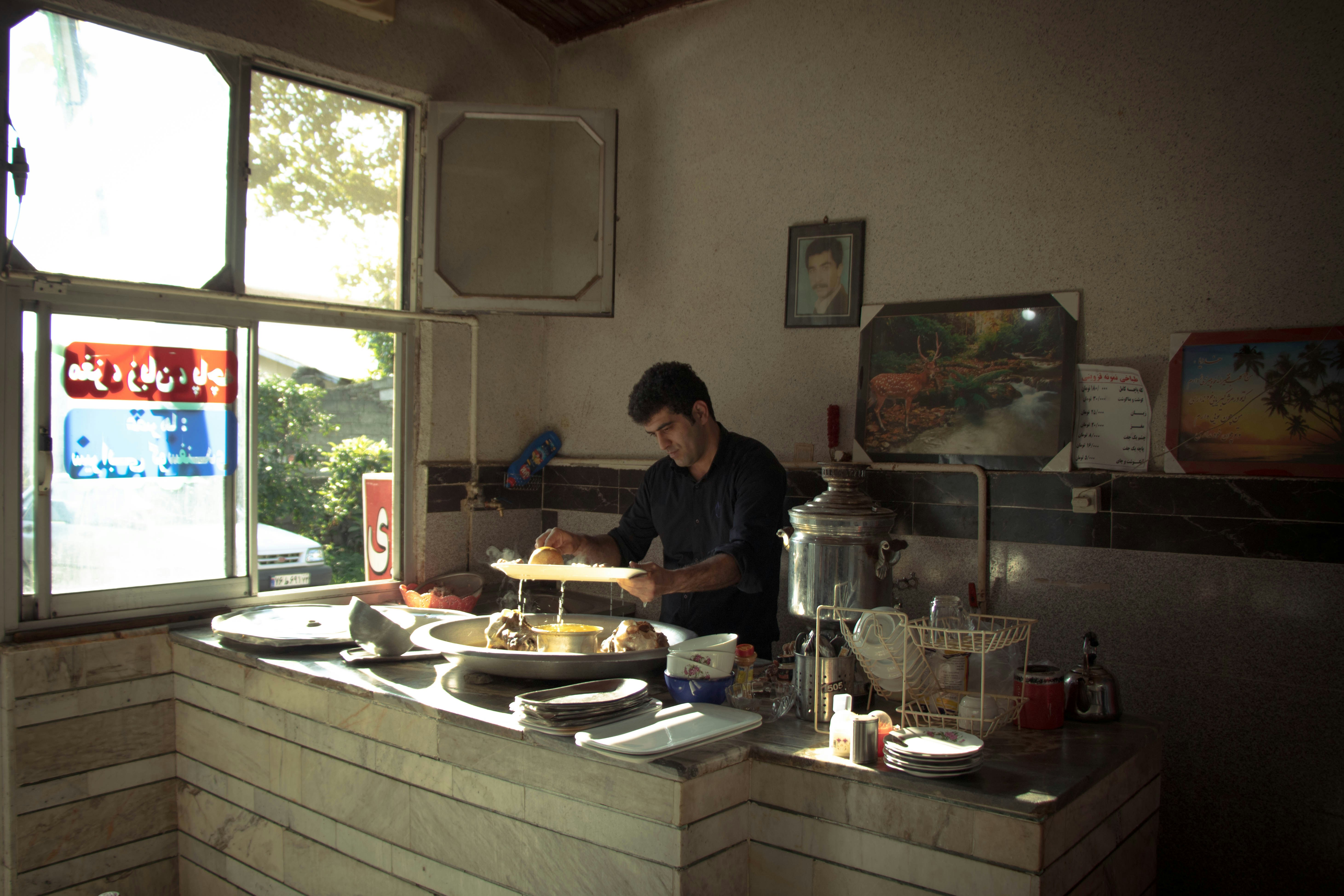 Sunlit Counter: A cook lines up plates in a quiet cafe kitchen