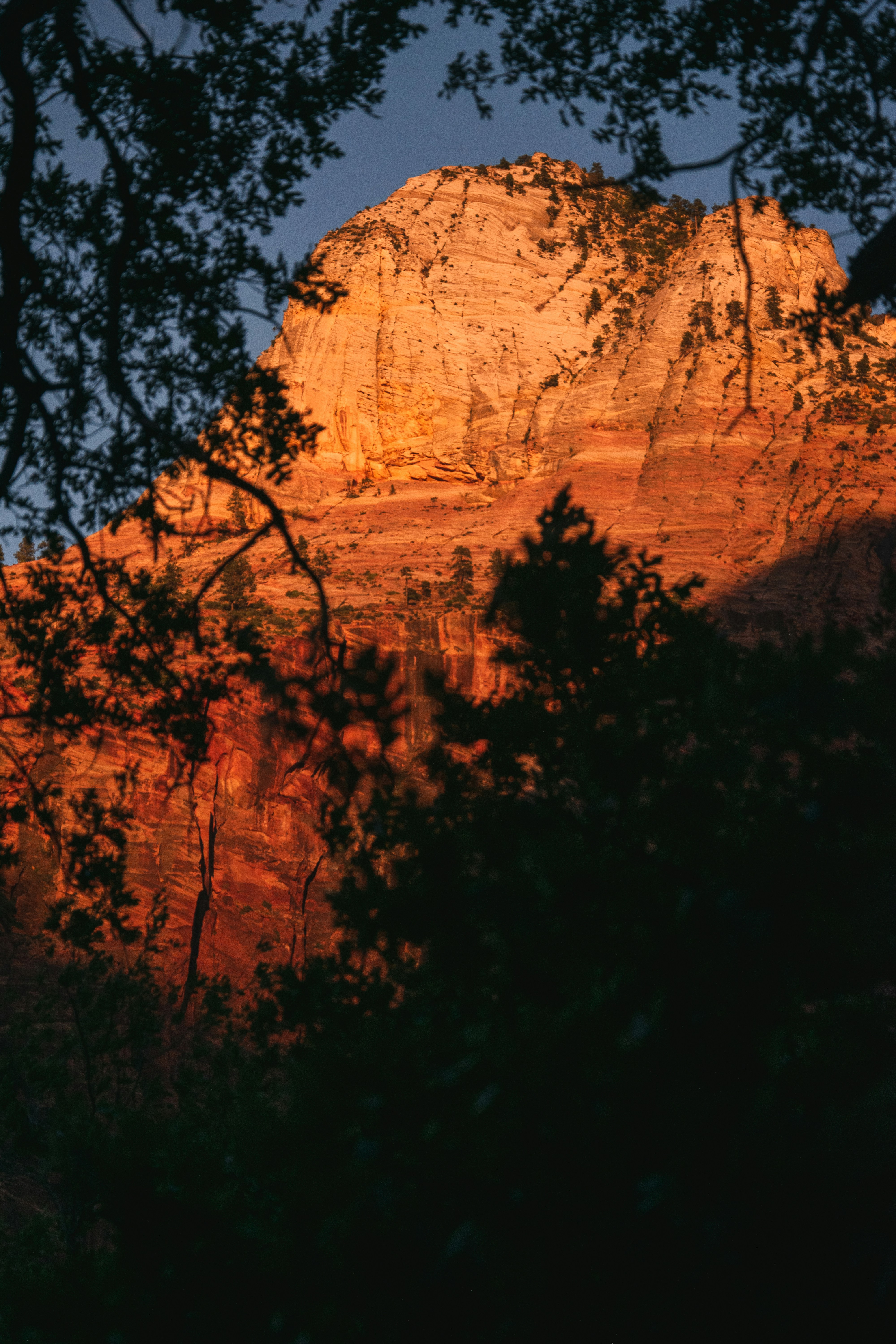 Crimson Cliff at Dusk: A Sun-Warmed Monolith Framed by Silhouettes