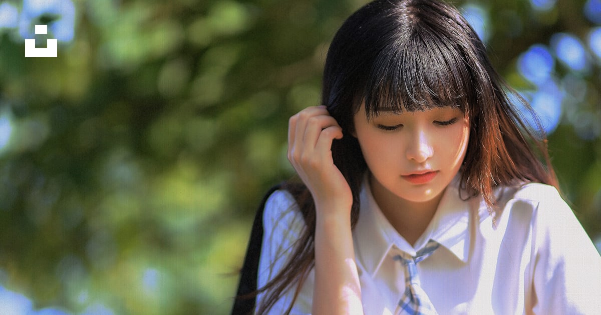 昼間、茶色の木製のベンチに座っている白いボタンアップシャツを着た女性の写真 Unsplashの人間の無料画像