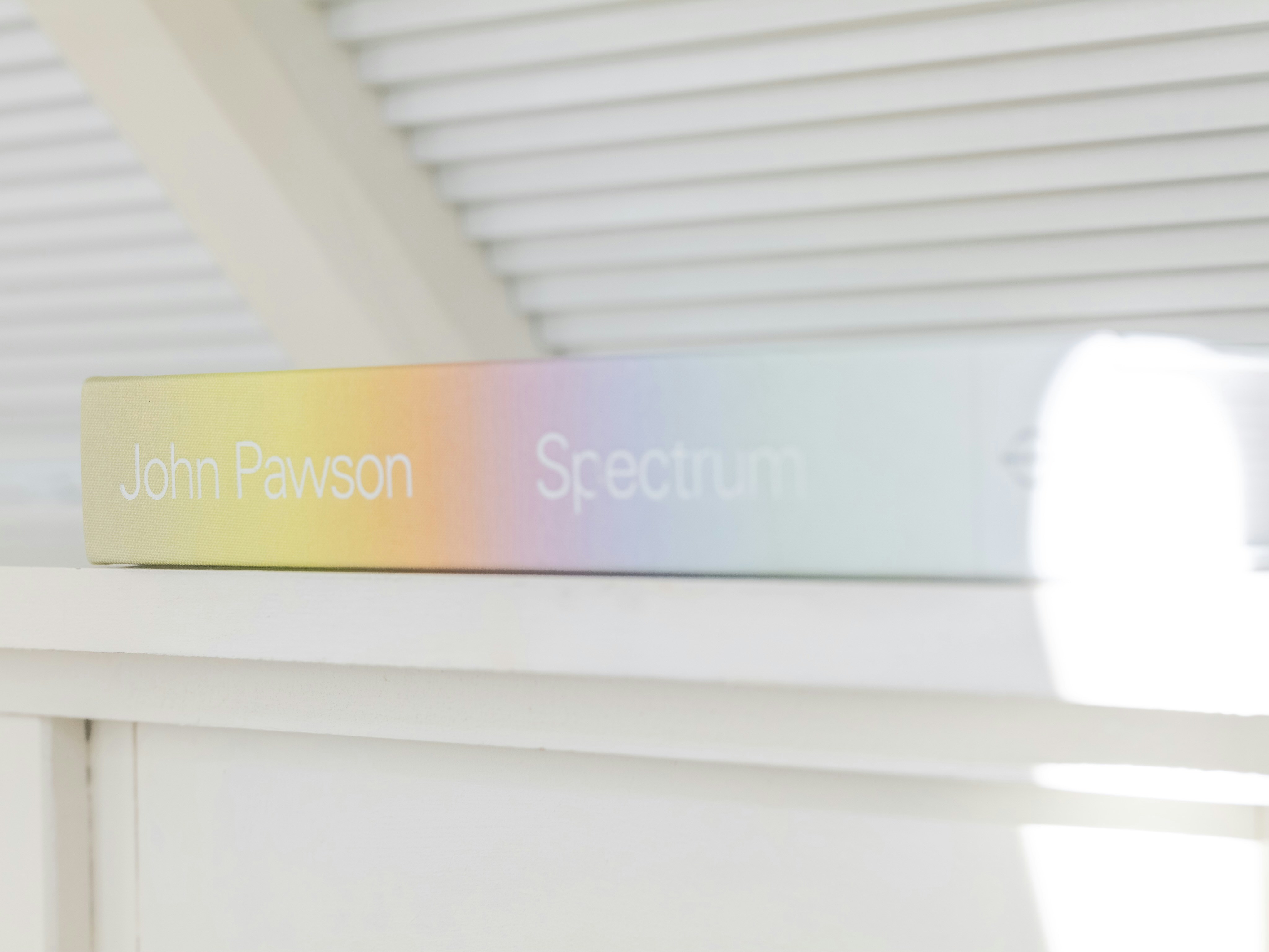 A close-up of the spine of 'Spectrum' by John Pawson, showcasing a gradient color transition against a minimalist background.