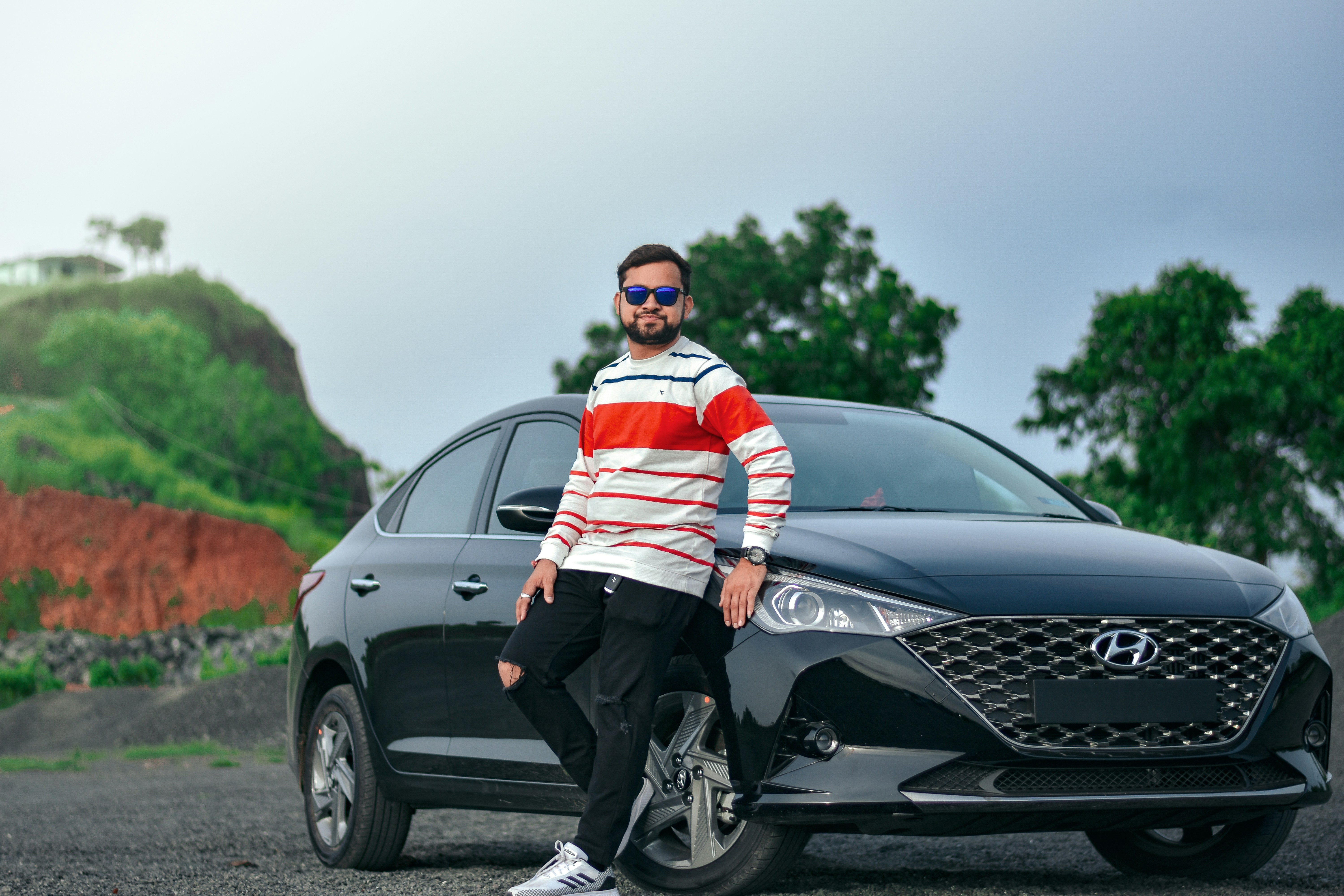 Rugged Calm: A man in striped sweater leans into a black Hyundai amid a quarry landscape
