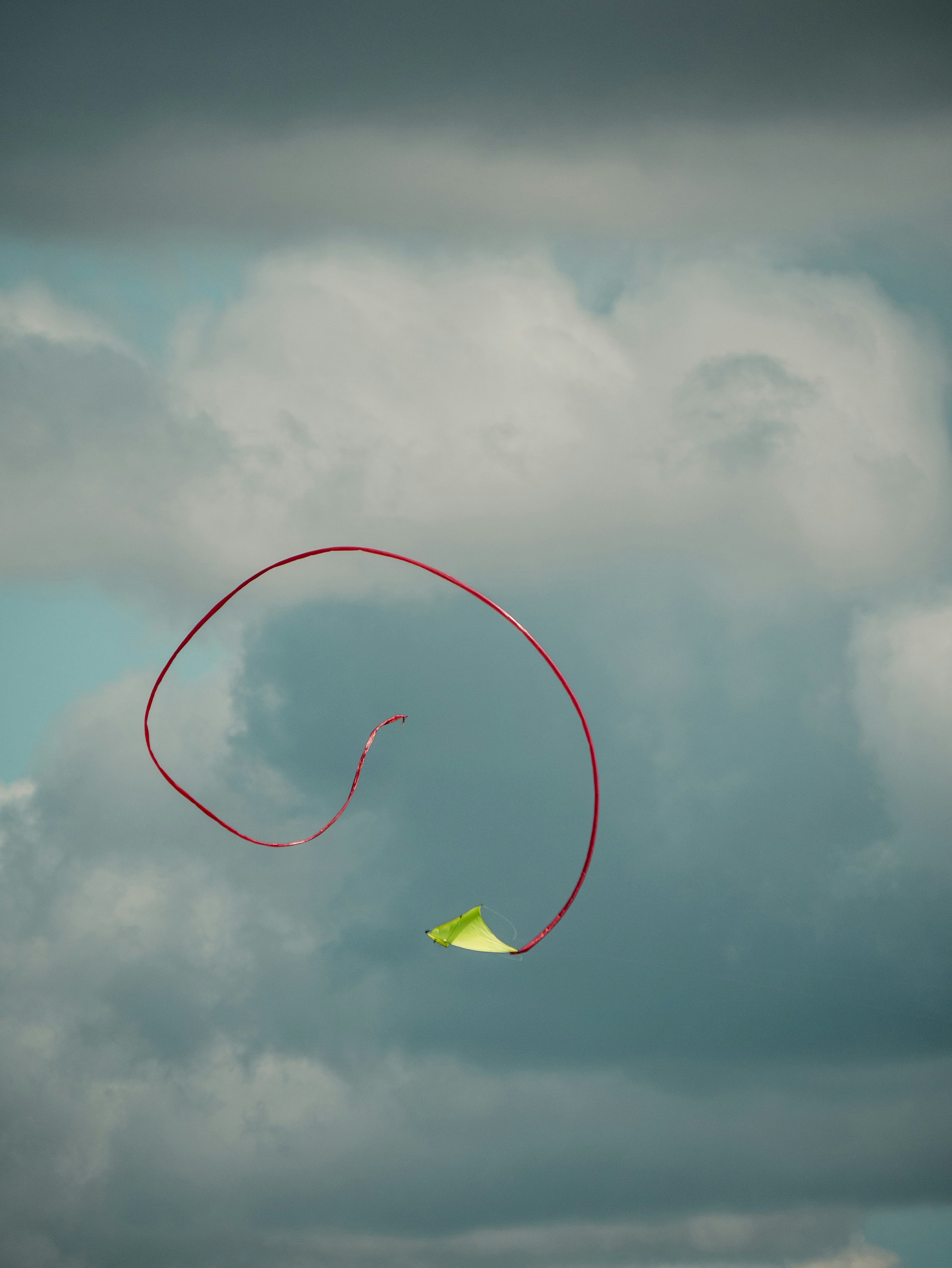 Spiral Arc over a Lime Kite: Red Tail Loops Through a Cloudy Sky