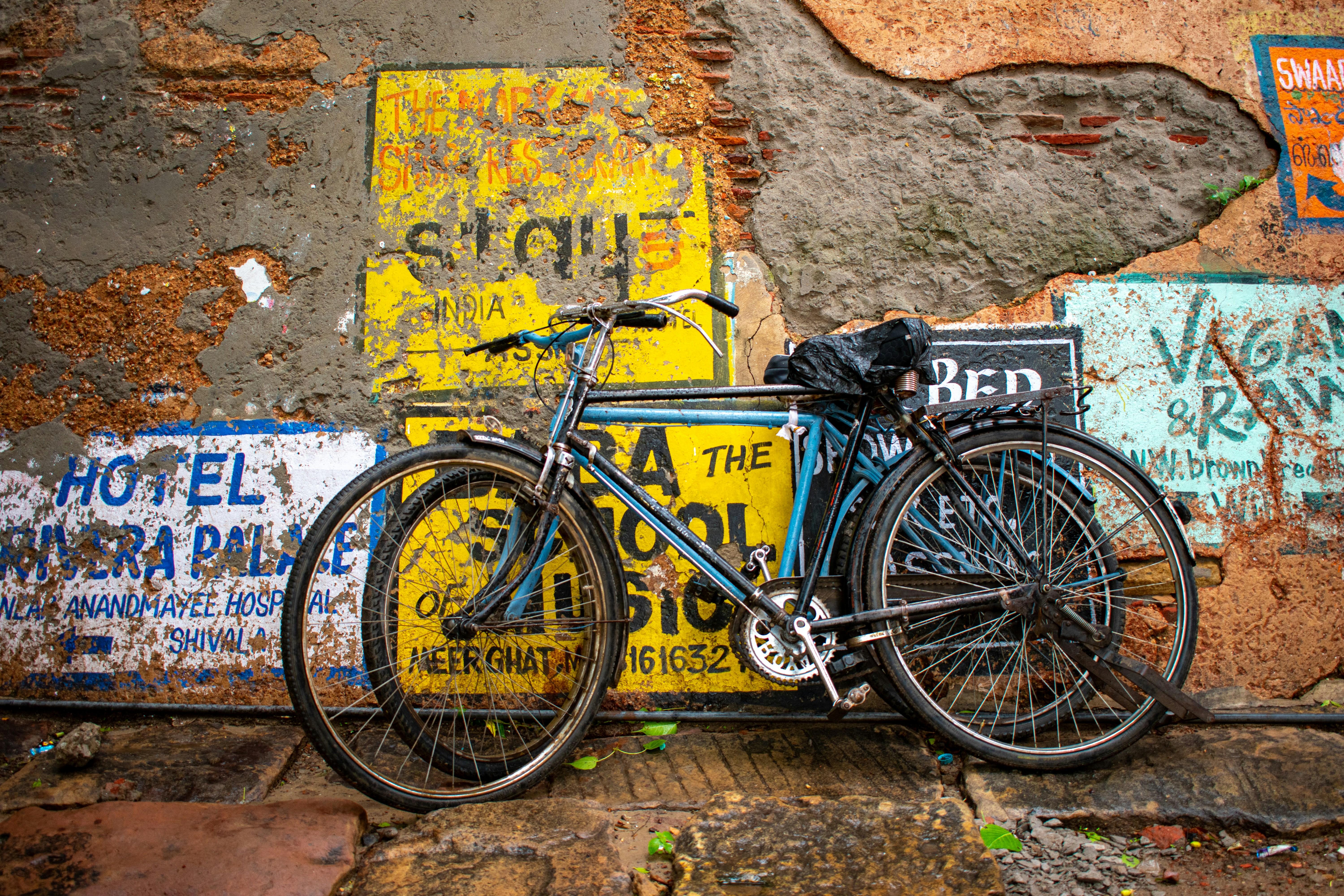 Bicycles leaning against a textured wall adorned with vibrant, weathered signs and graffiti.
