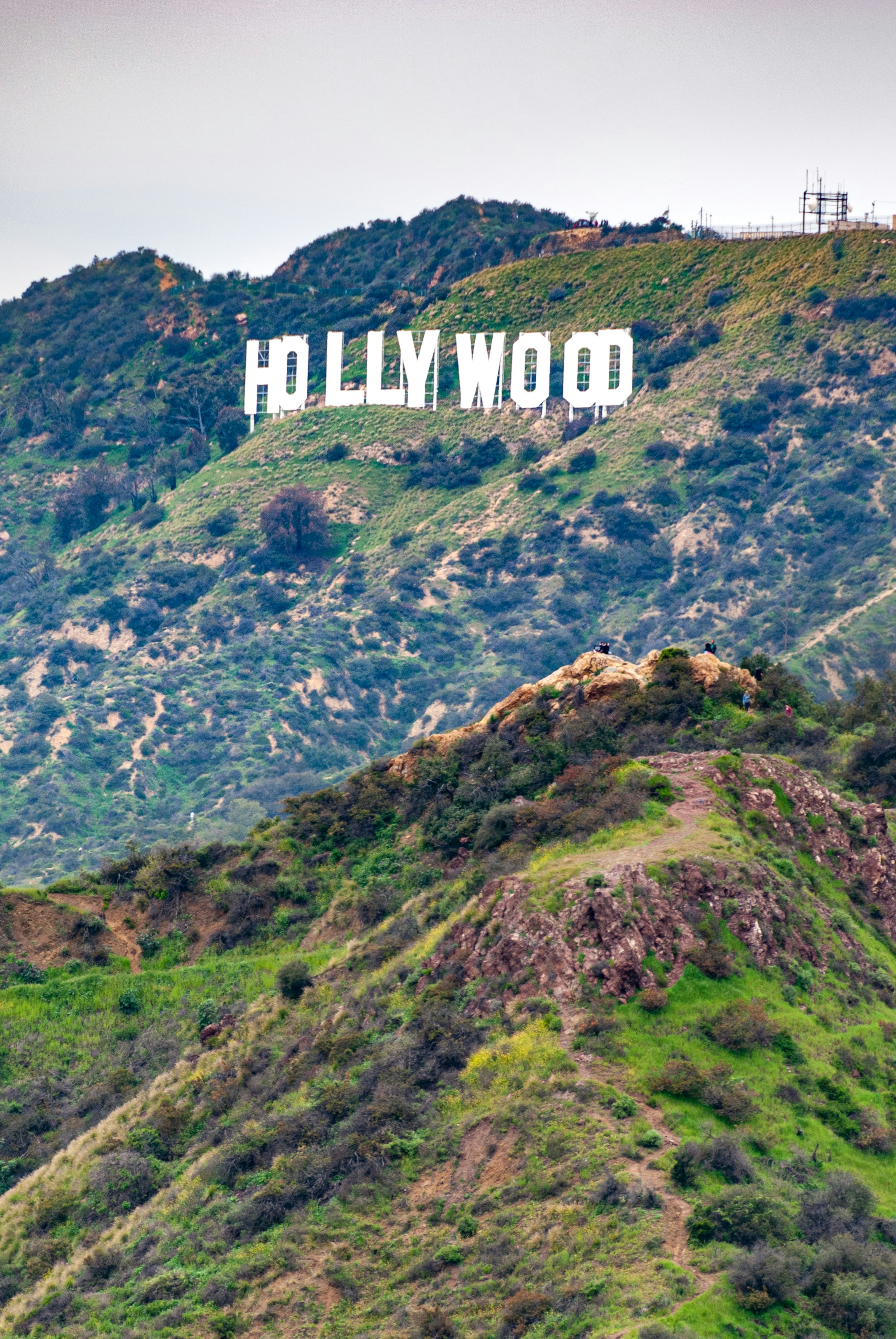Hollywood sign perched on a hillside, surrounded by lush greenery and rugged terrain.