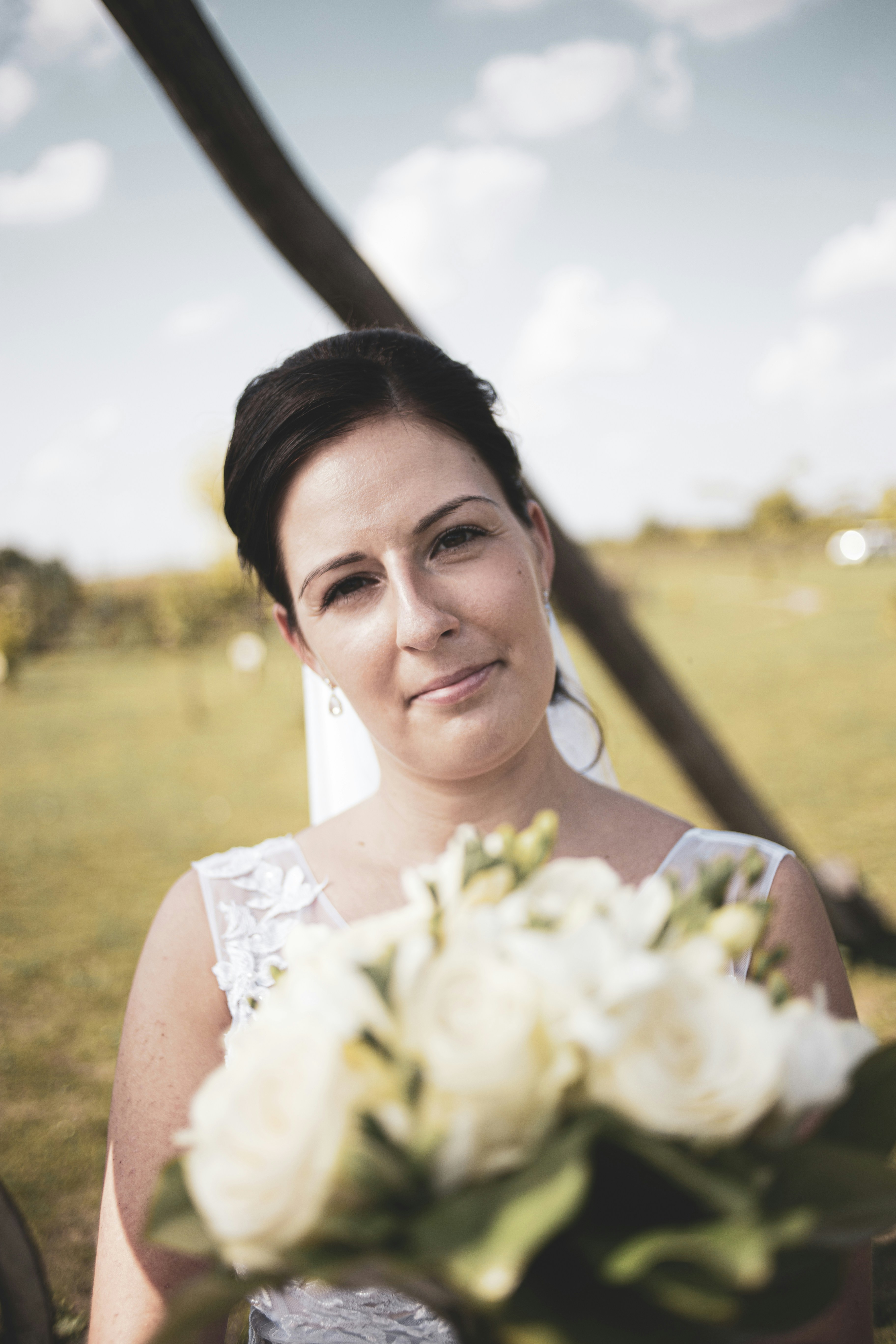 Sunlit Bride with Bouquet Against a Rustic Backdrop