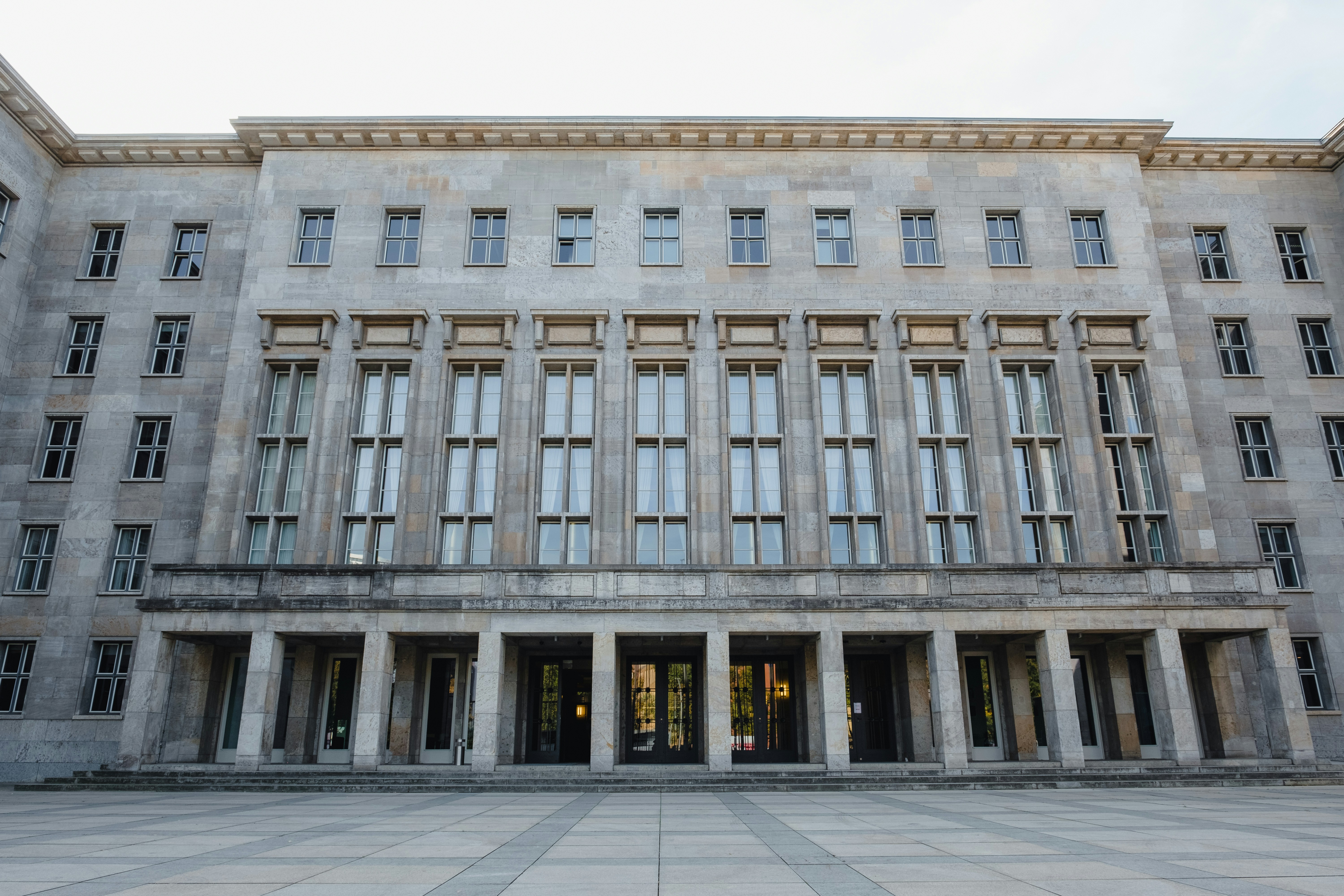 Imposing concrete building facade showcasing symmetrical design and large windows, inviting natural light into the interior.