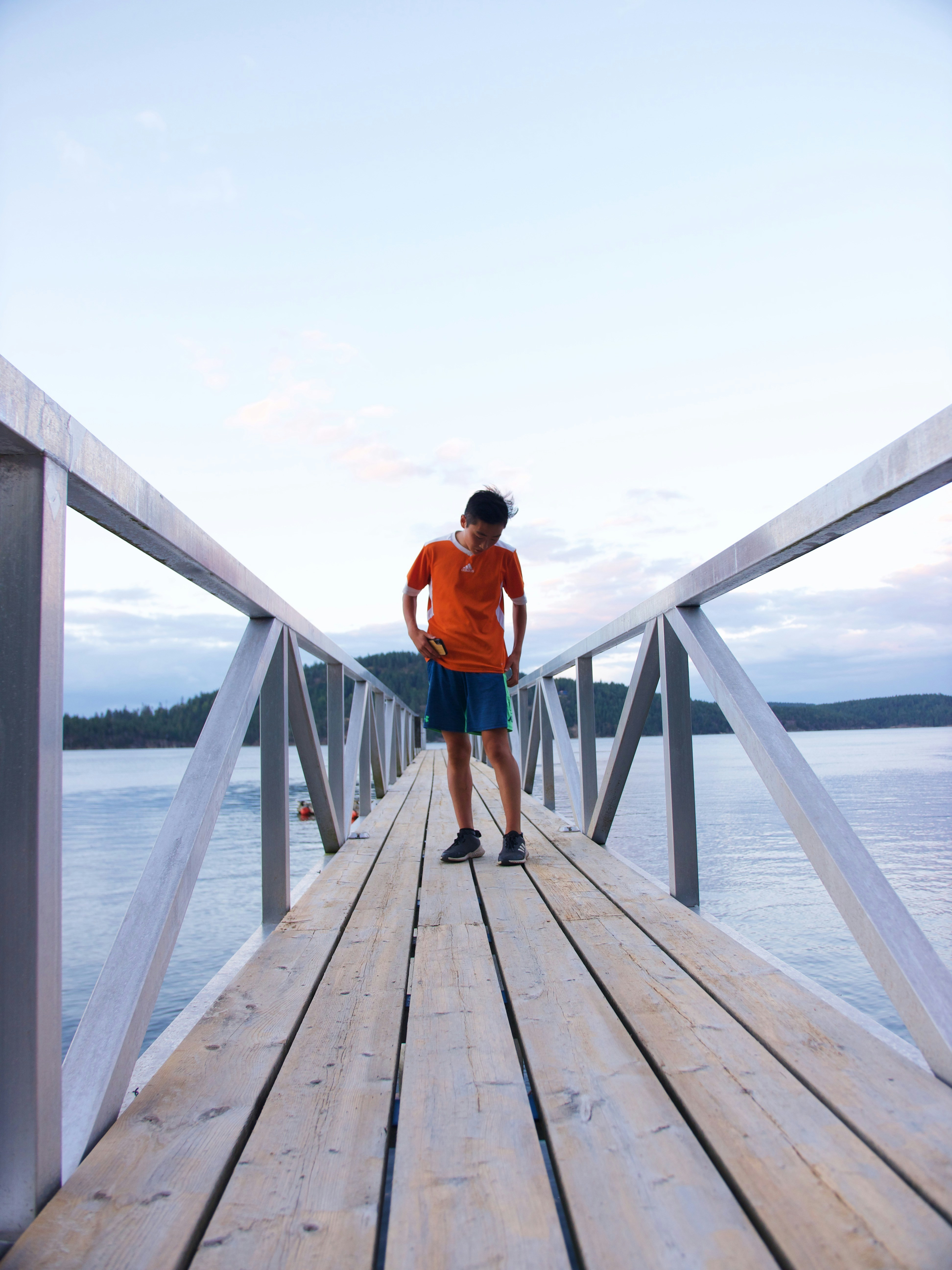Woman in blue tank top and black shorts standing on wooden dock during ...