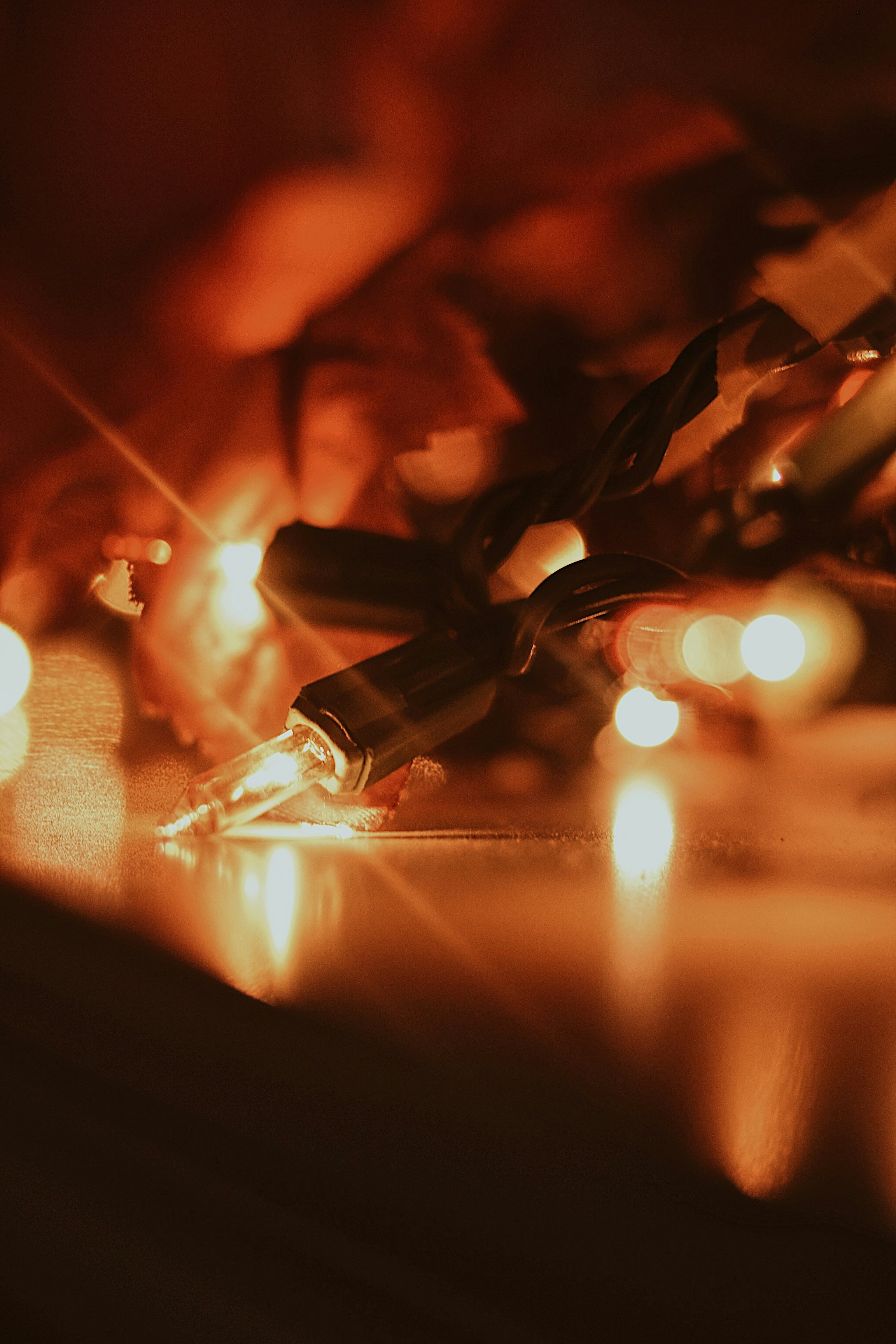 Amber Tangle: Macro of Warm LED Strings on a Shimmering Surface