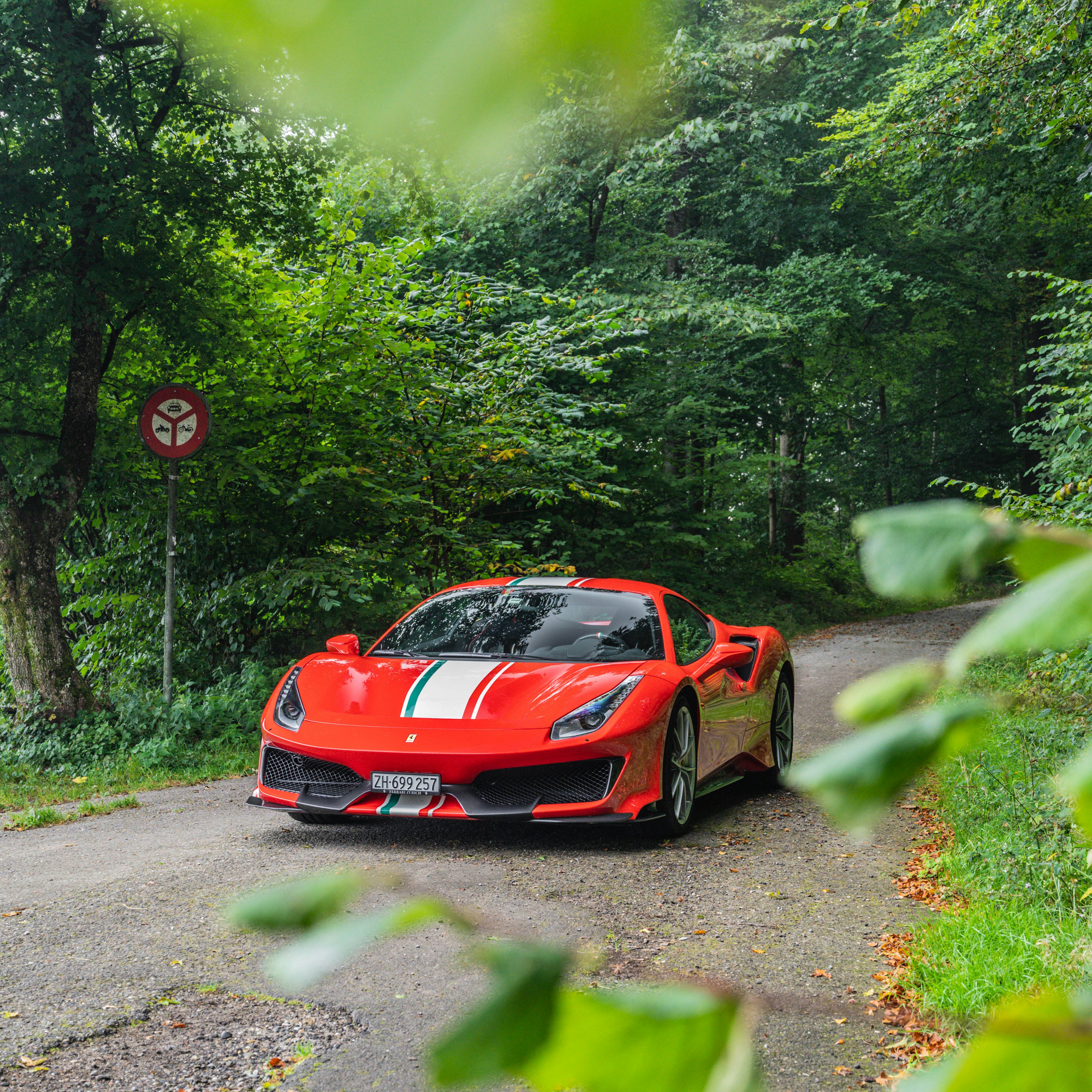Red ferrari coupe on road in between green trees during daytime photo ...