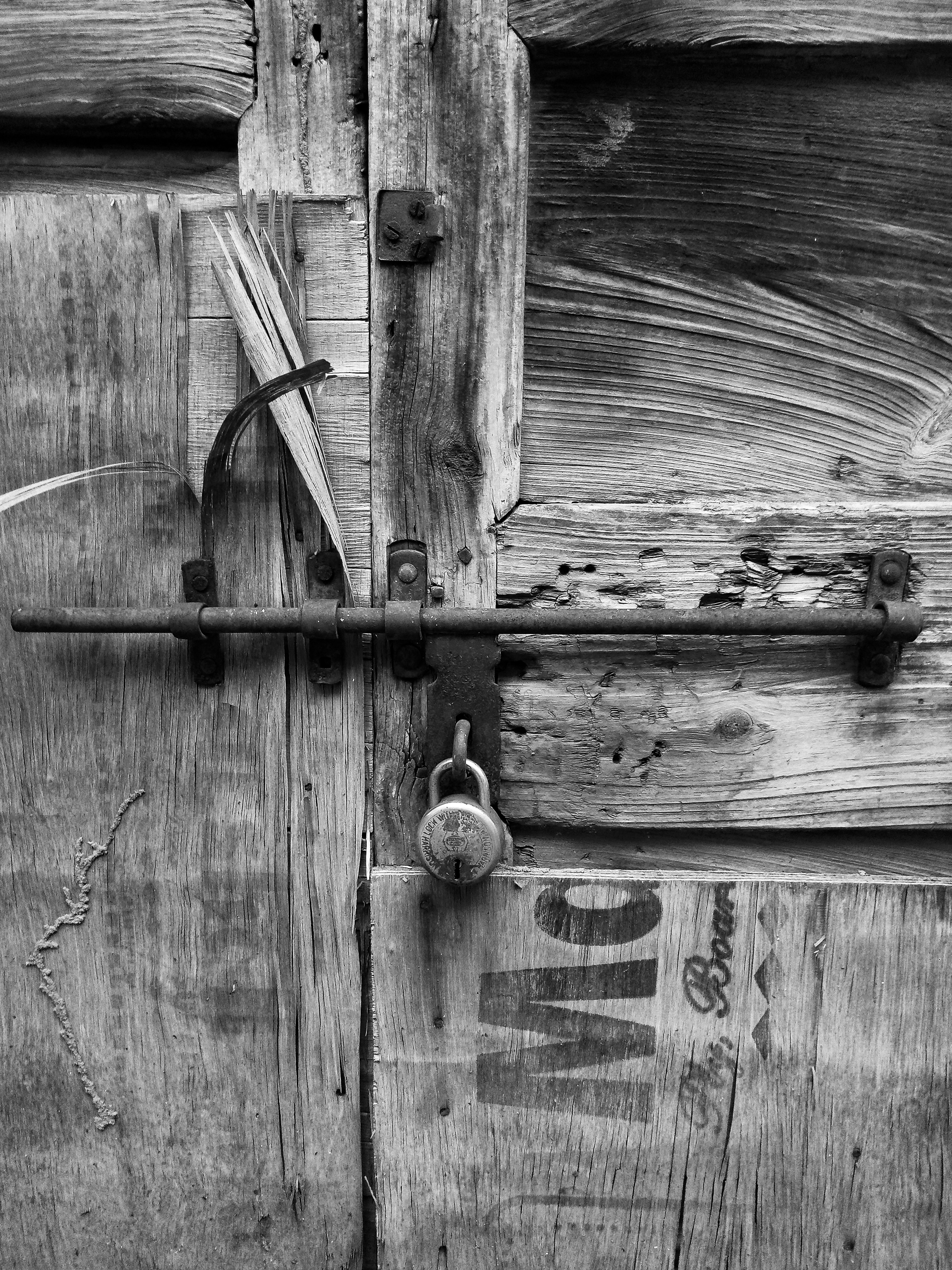 Close-up of a weathered wooden door with a rusty lock and latch, showcasing the texture and character of aged materials.