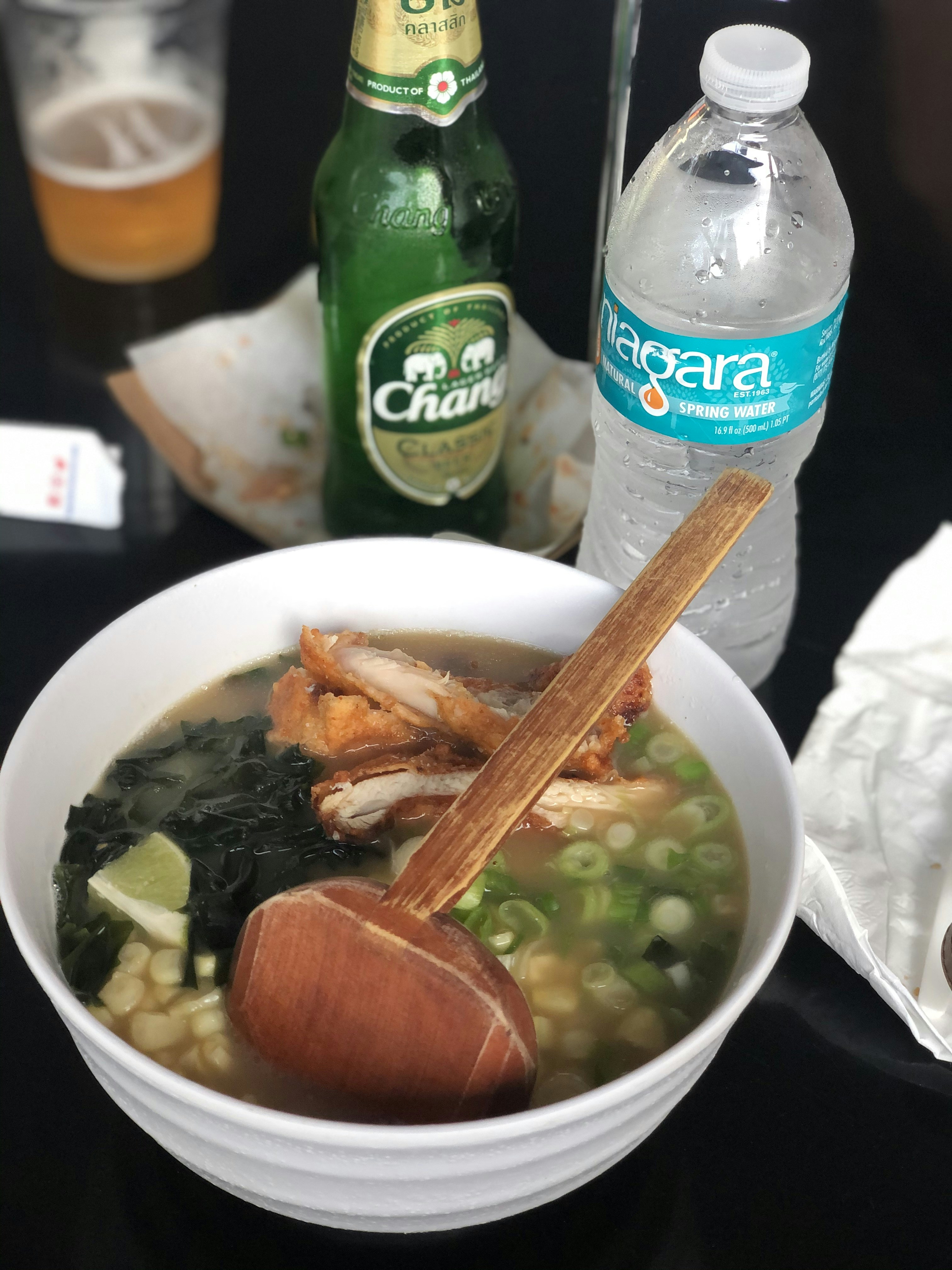 Delicious bowl of ramen featuring tender chicken, seaweed, green onions, and lime, accompanied by refreshing beverages.
