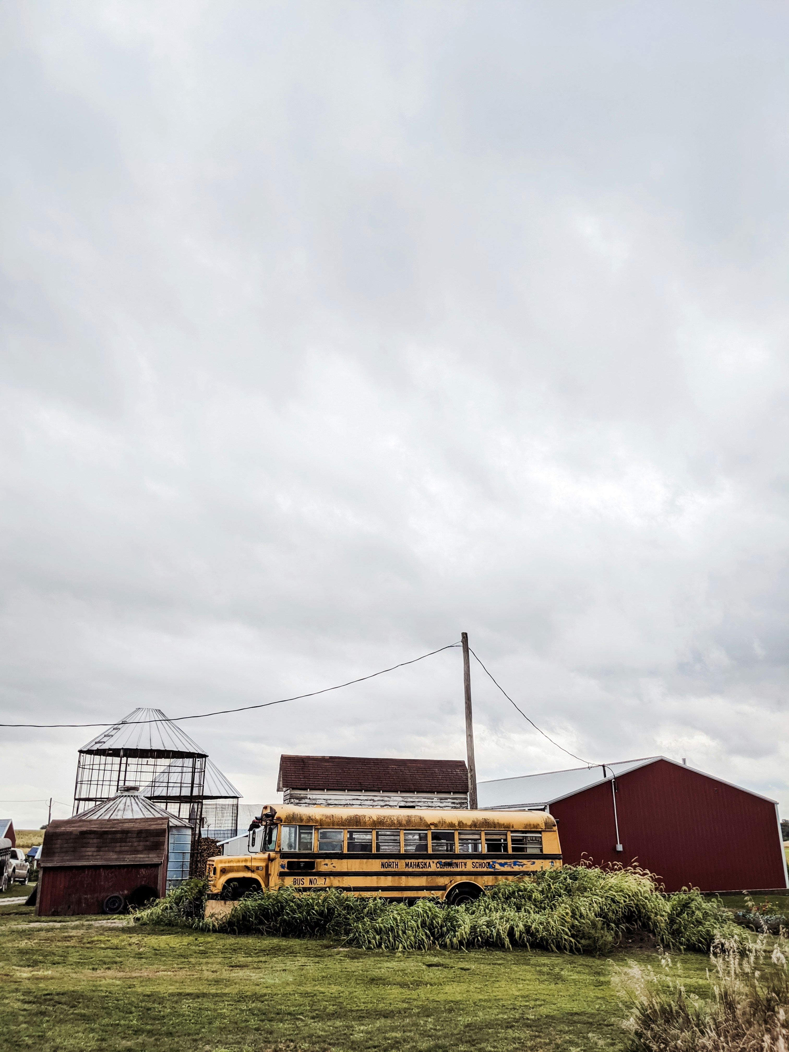 Lone Yellow School Bus Anchored in a Quiet Farmyard Under Cloudy Skies