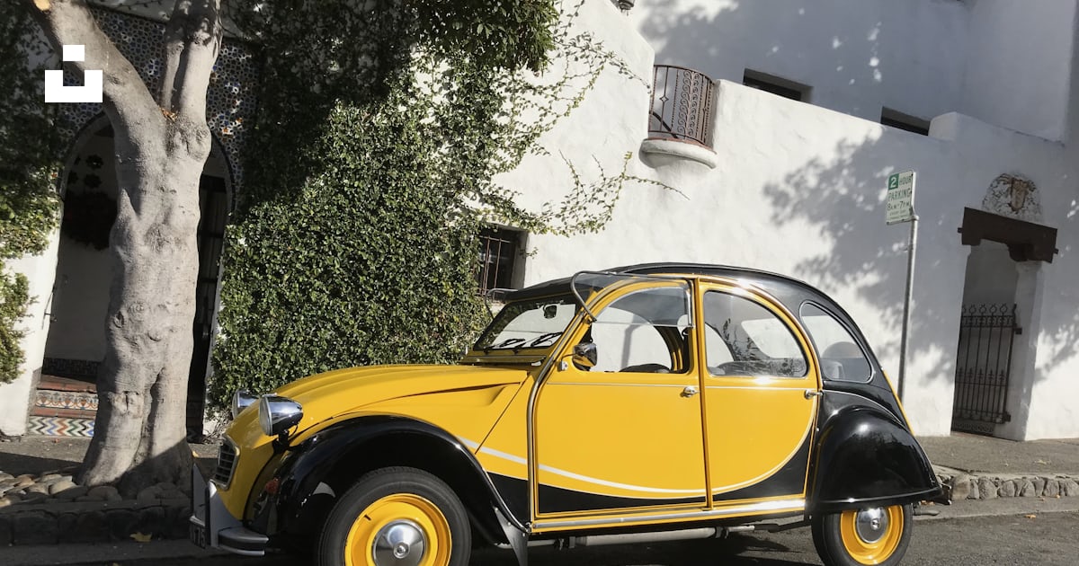 Yellow And Black Volkswagen Beetle Parked Beside White Concrete