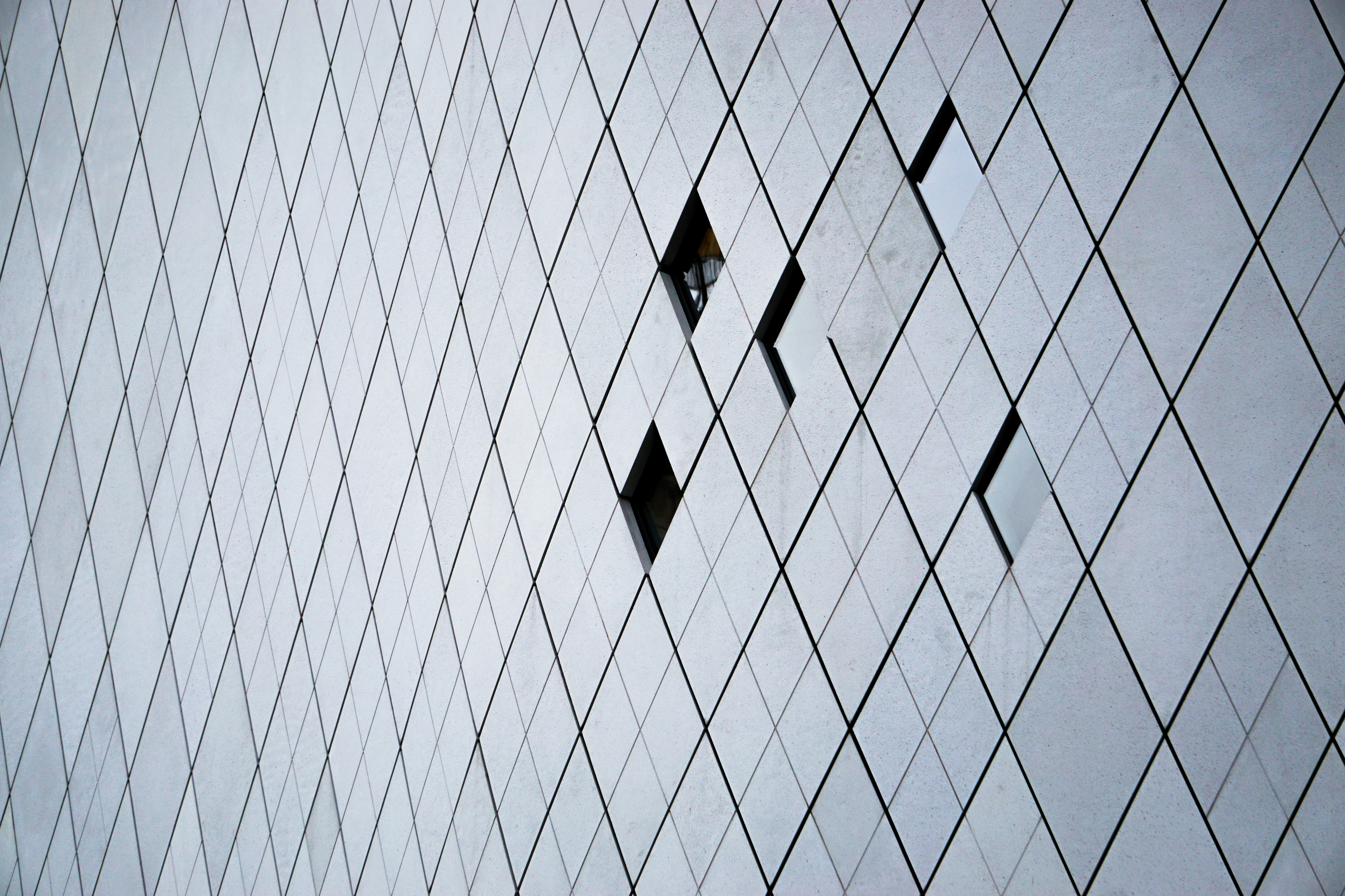 Abstract architectural detail featuring a diamond-patterned facade with irregular window openings reflecting light.