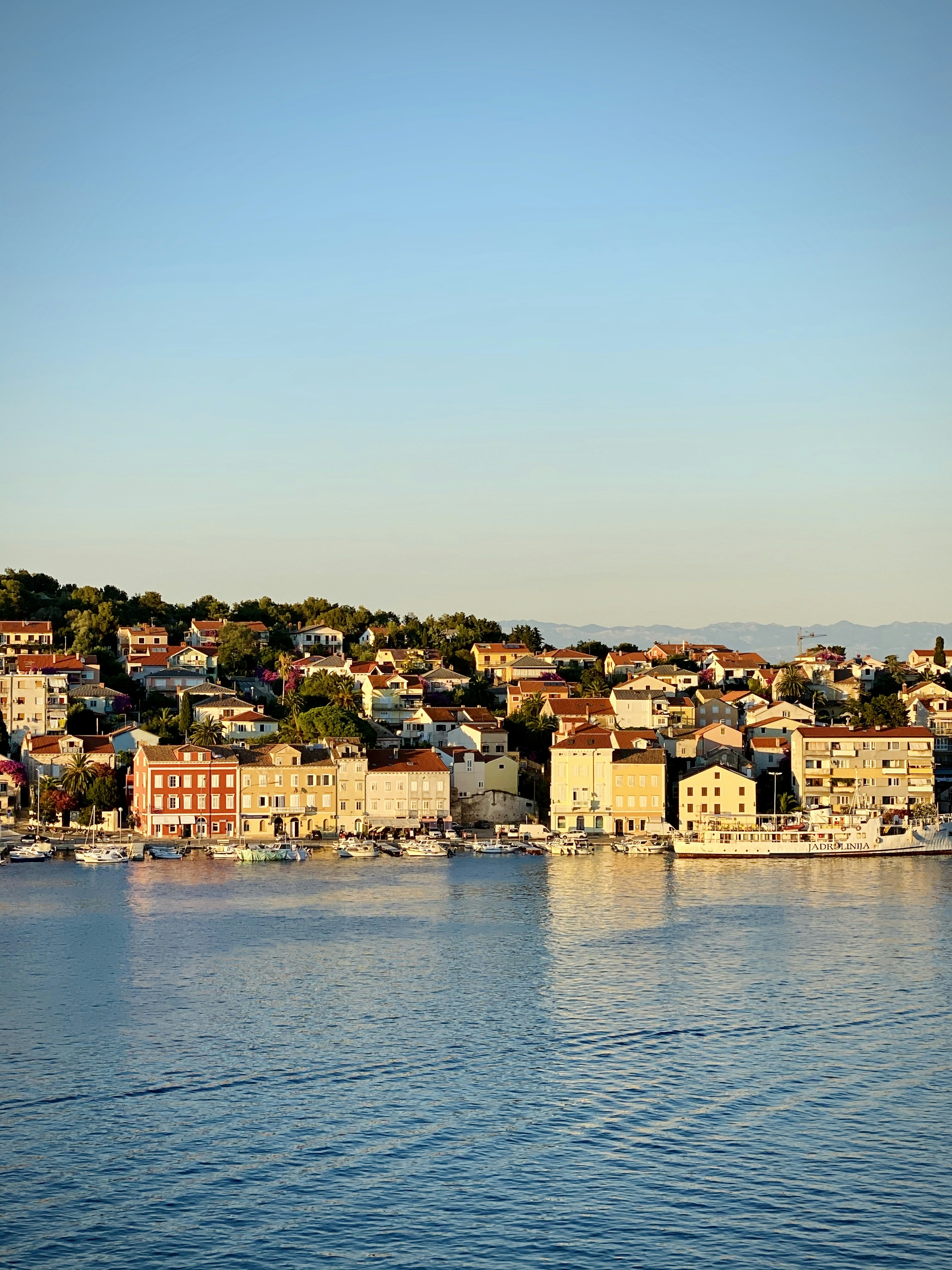 Charming coastal village with colorful houses lining the waterfront, reflecting in the calm water under a clear sky.