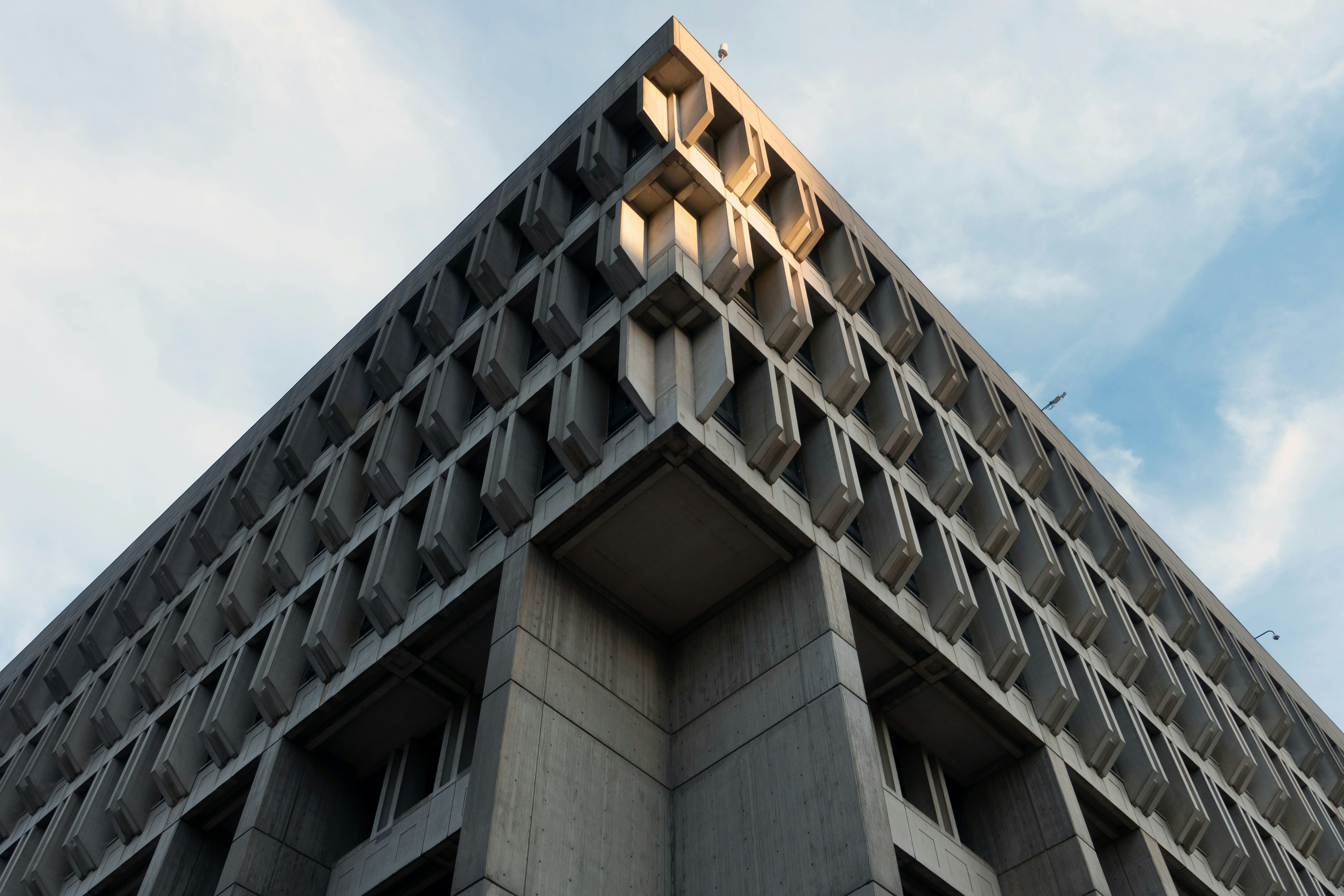 Abstract architectural detail showcasing a concrete building's unique geometric patterns and interplay of light. The structure's angular design emphasizes modernist aesthetics.