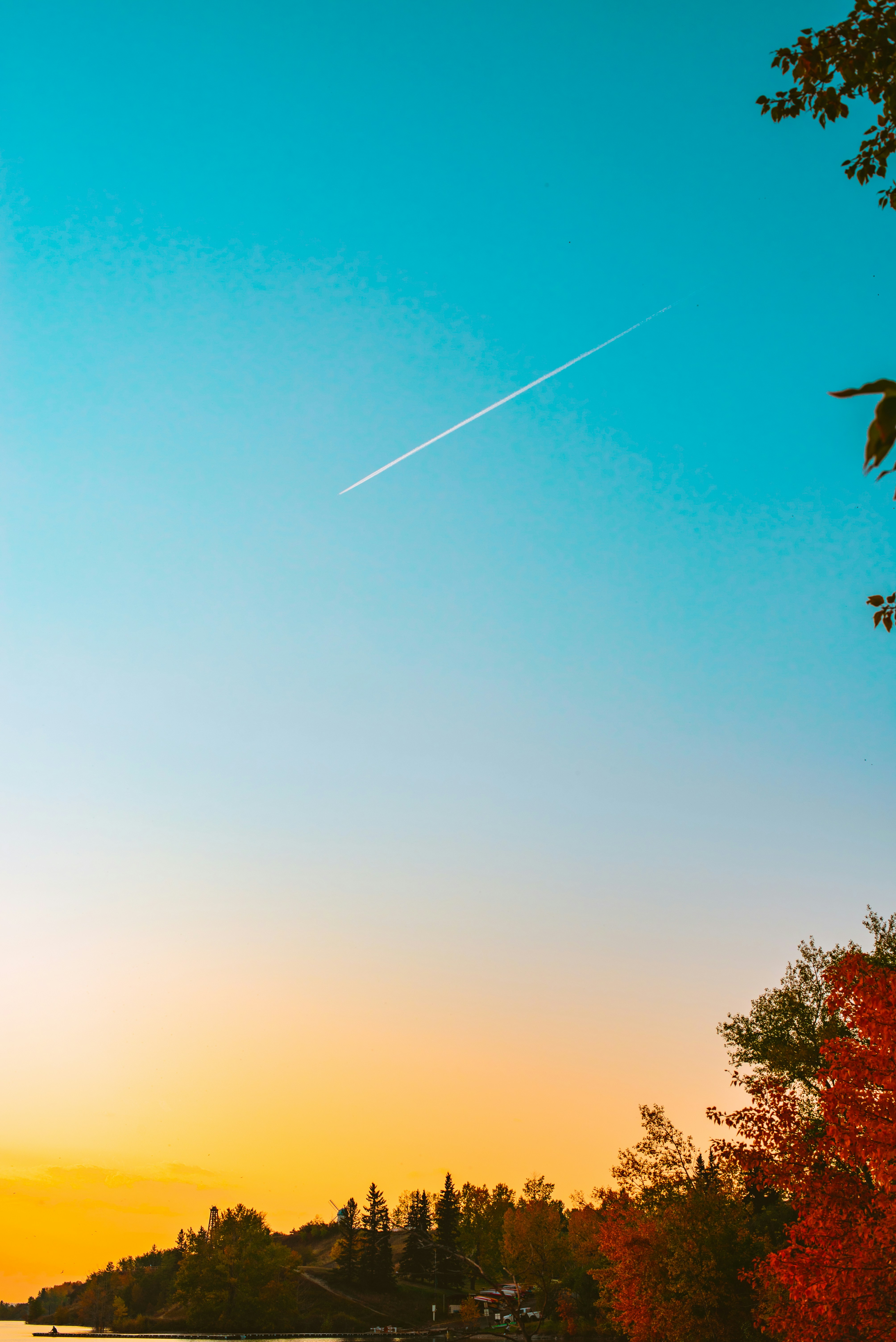 Contrail Across a Two-Tone Sunset Over a Tranquil Lakeshore