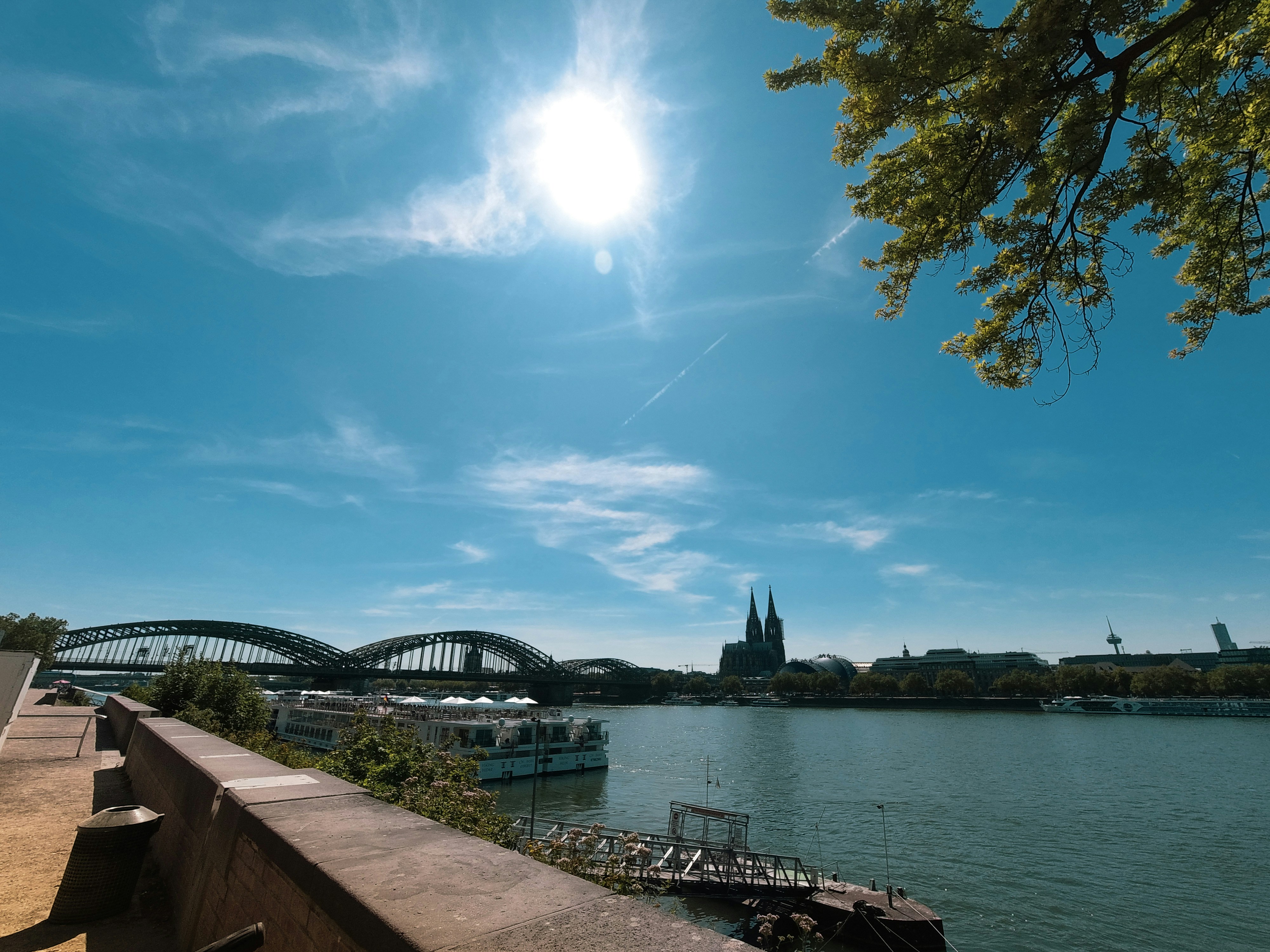 A scenic view of the river with bridges and a cathedral in the background, under a bright blue sky. The image captures the essence of a vibrant urban landscape.