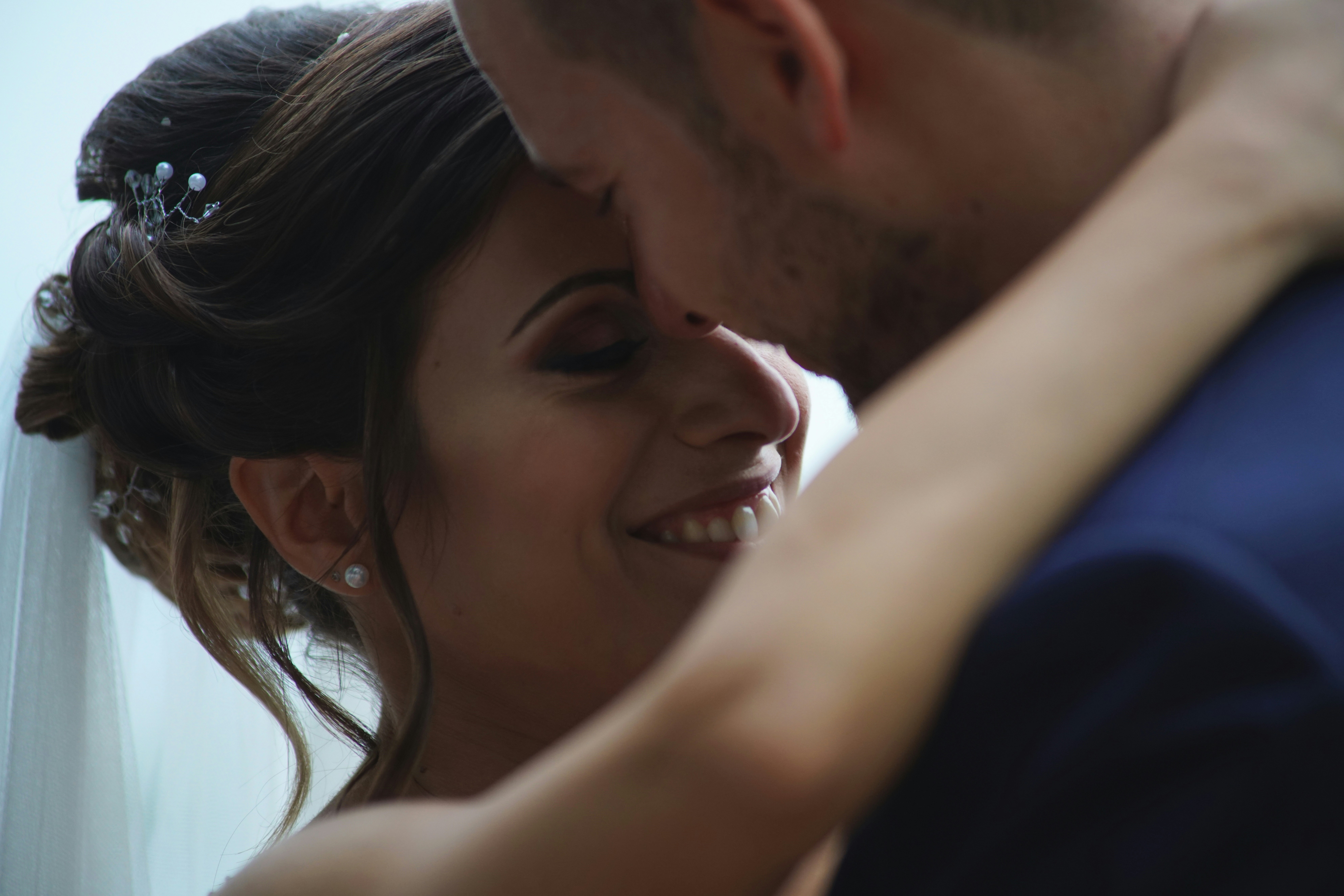 Bride and groom sharing an intimate moment, their foreheads touching as they smile at each other, surrounded by soft lighting.
