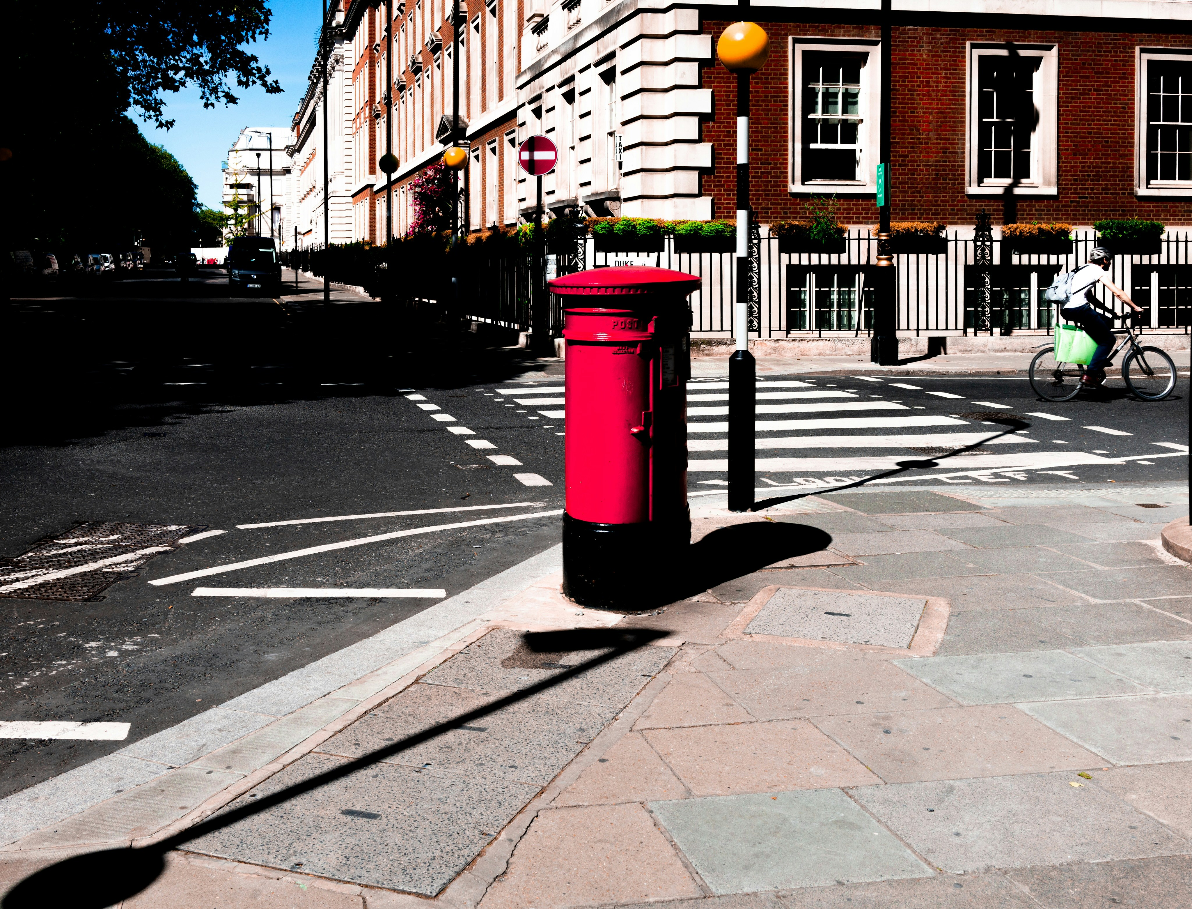 Crimson Post Box at a Sunlit Urban Crosswalk