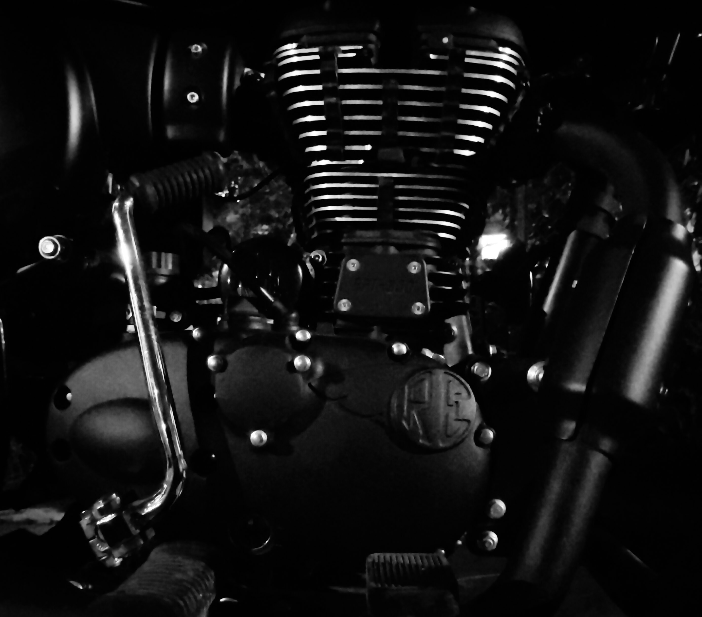 Close-up of a motorcycle engine showcasing intricate details and robust design elements in a monochromatic setting.