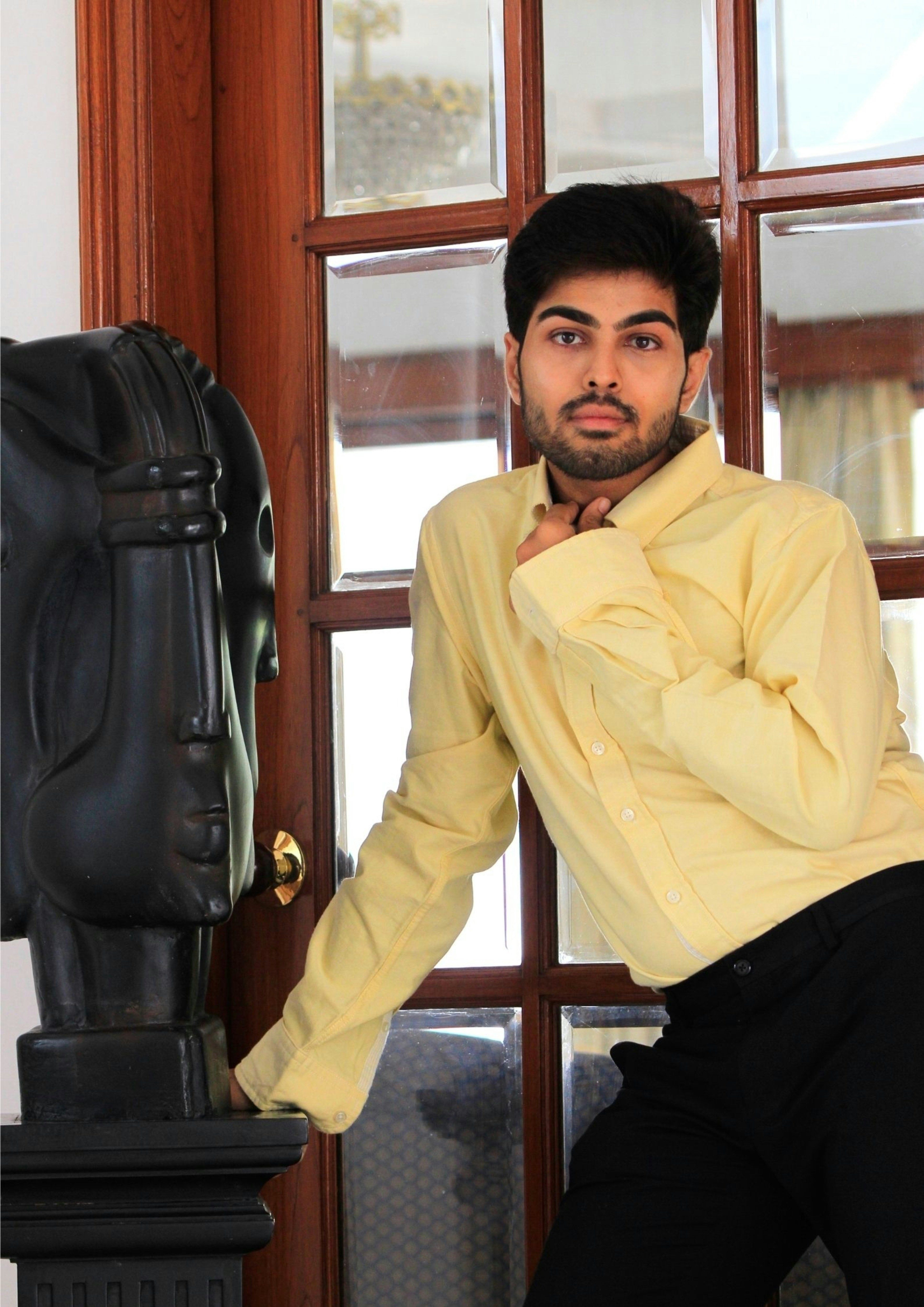 Man in yellow dress shirt and black pants sitting on black leather ...