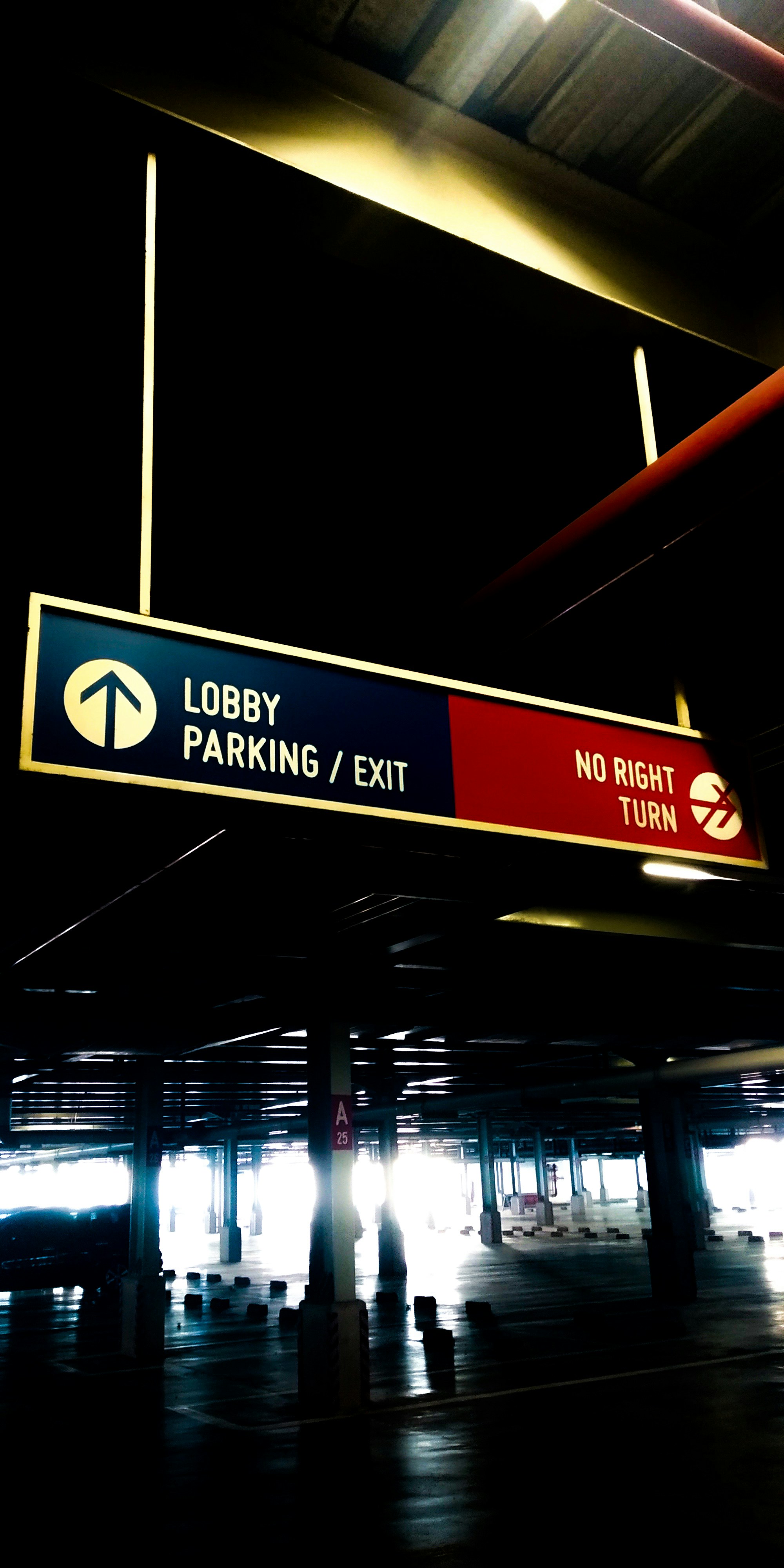 A sign hanging from the ceiling of a parking garage photo – Free ...