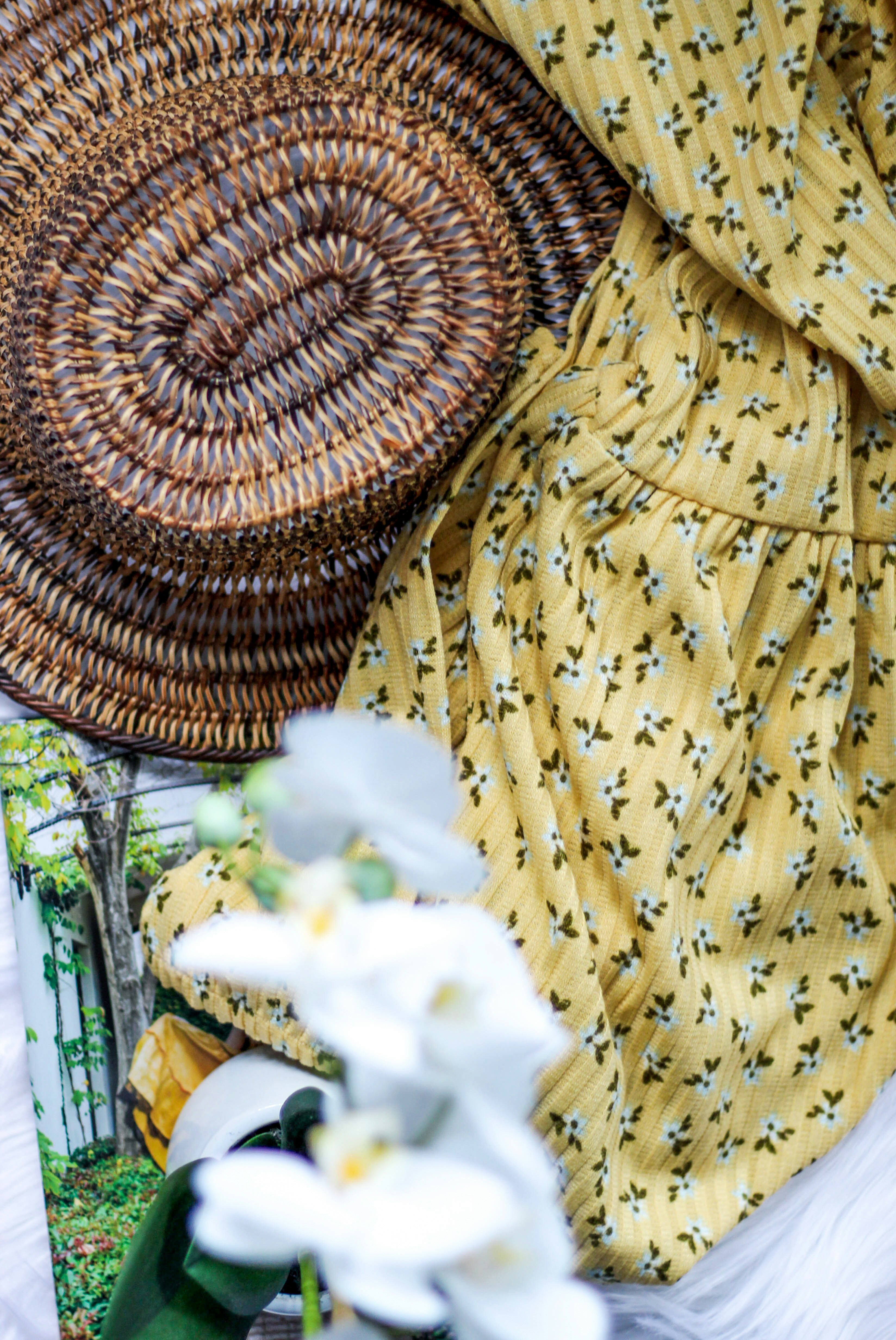 Spiral Straw Hat Meets a Sunlit Yellow Floral Dress in a Quiet Still-Life