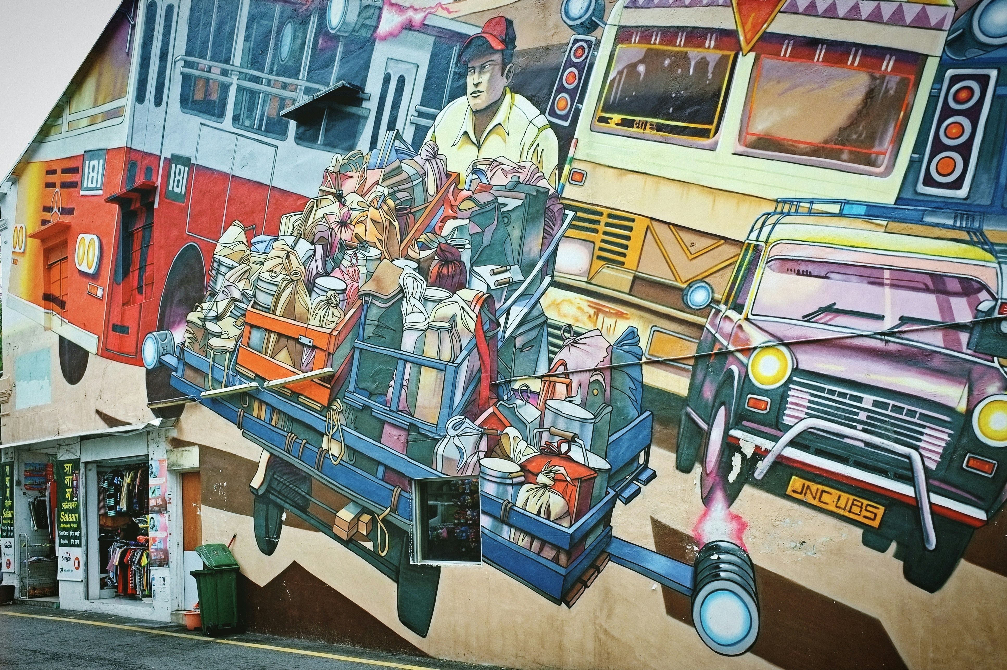 Vibrant mural depicting a man transporting goods on a cart, surrounded by dynamic vehicles and urban elements. The artwork captures the essence of city life.
