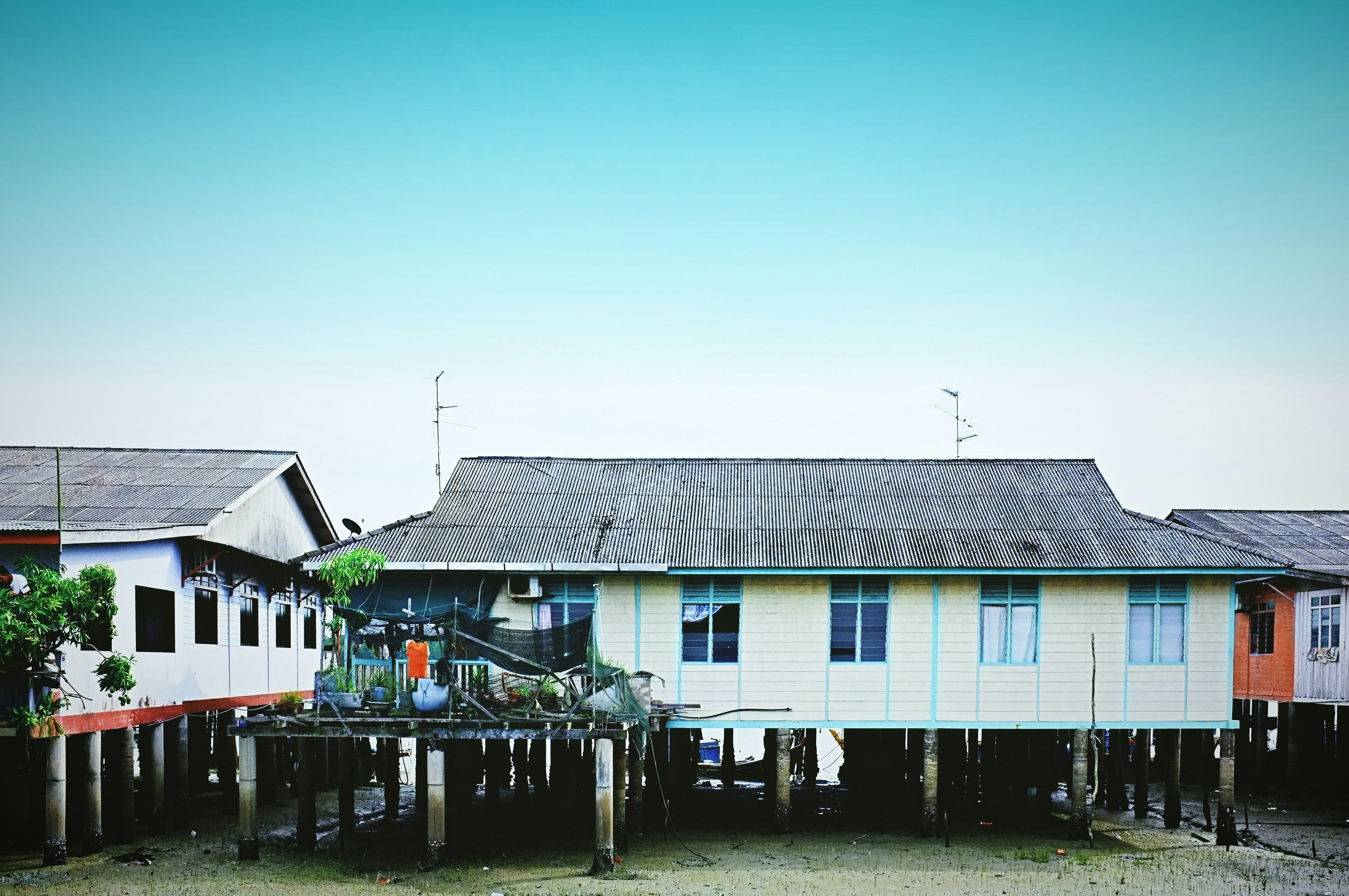 Colorful houses on stilts over calm water under a clear blue sky.