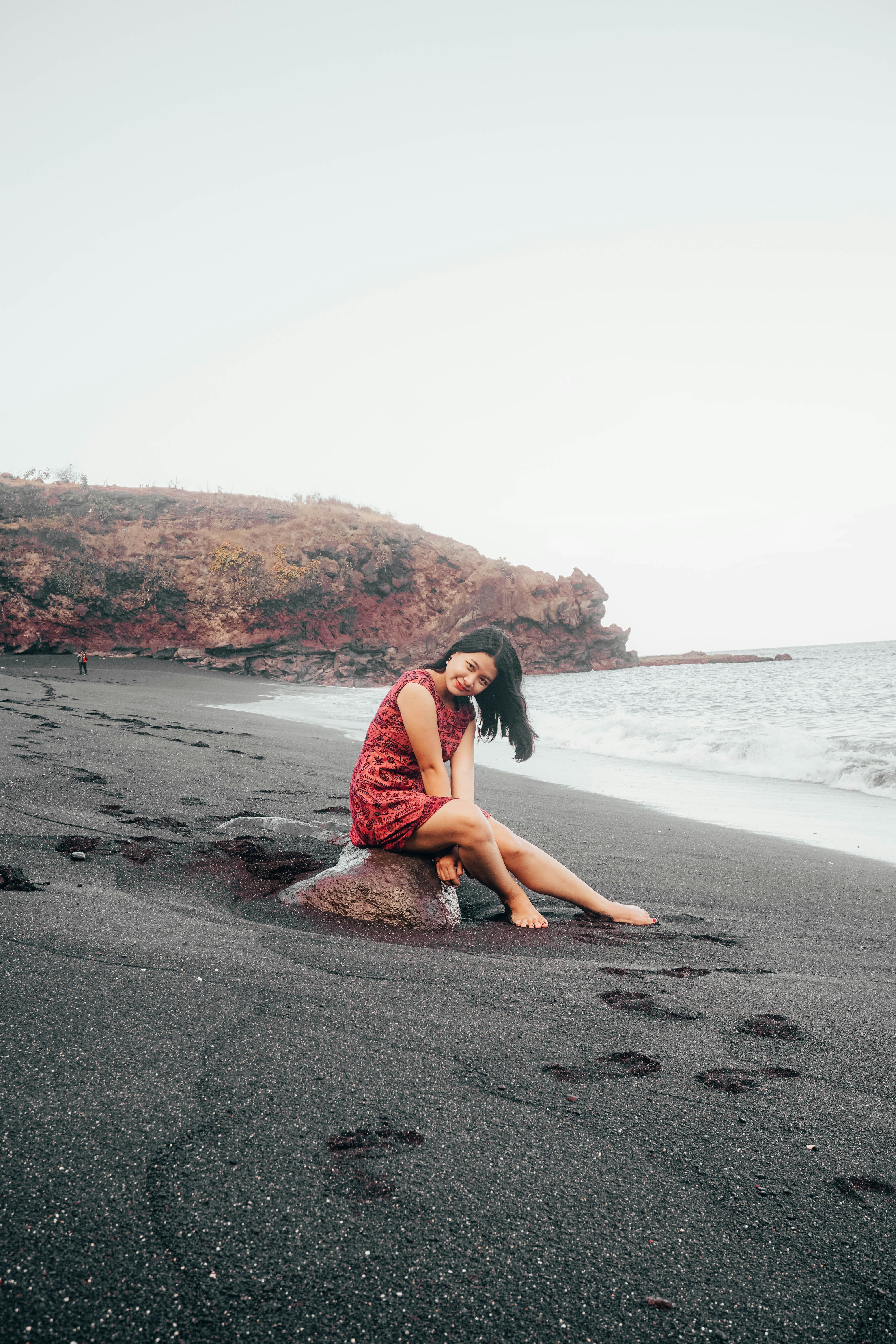 Red Dress by the Shore: Quiet Moment on a Volcanic Beach