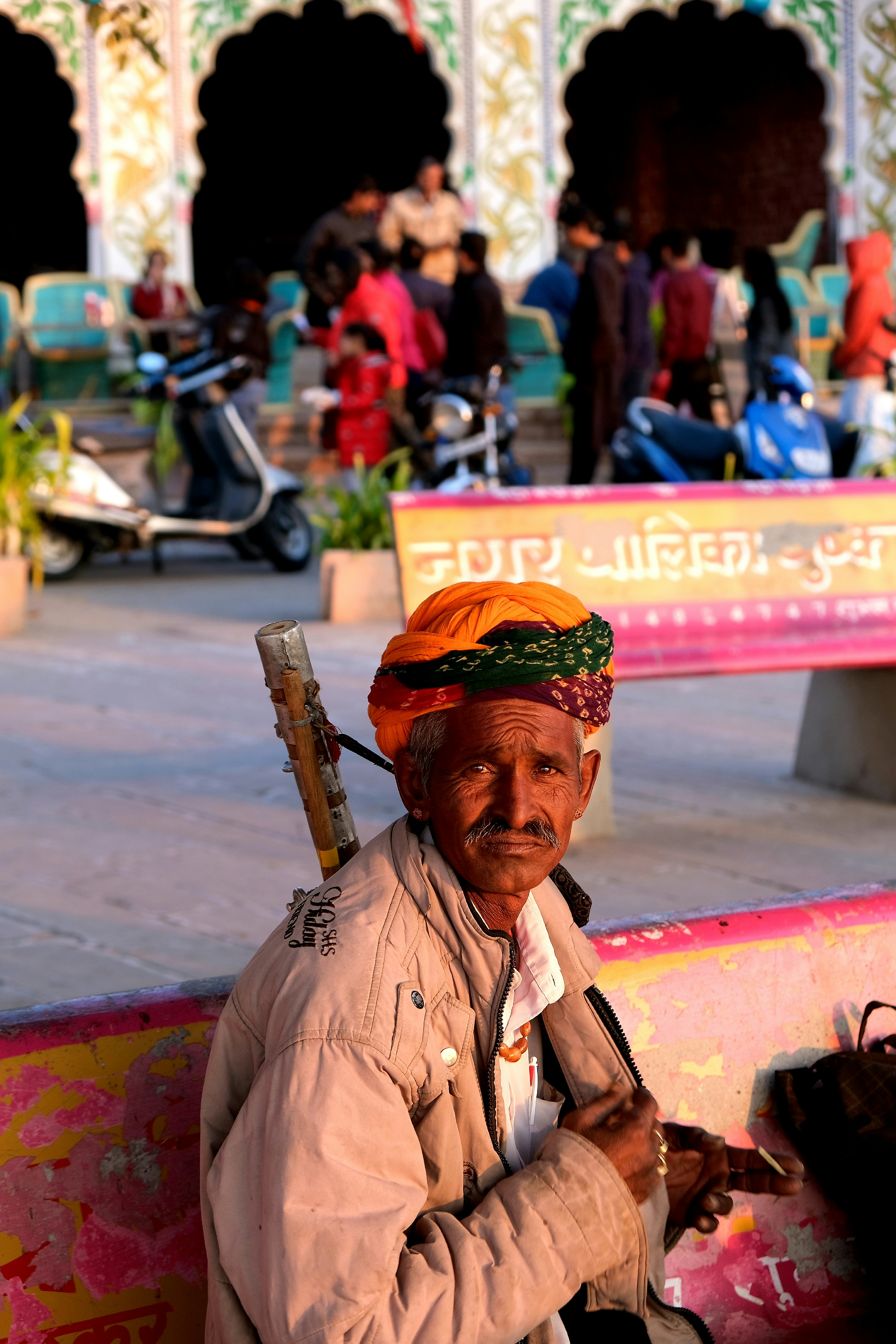 Sunlit Gaze: An Elder with a Stave in a Bustling Indian Square