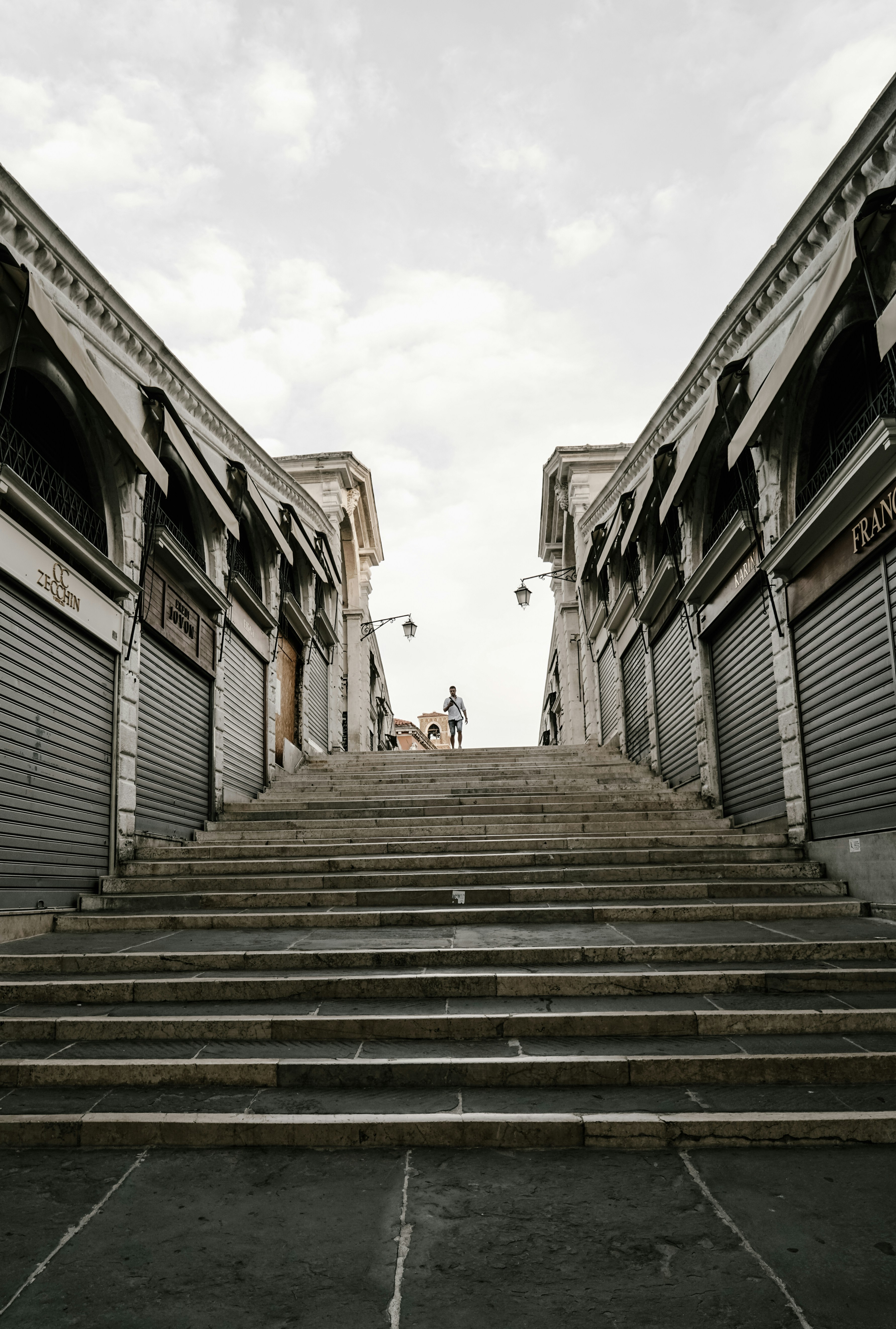 2 person walking on stairs between concrete buildings during daytime