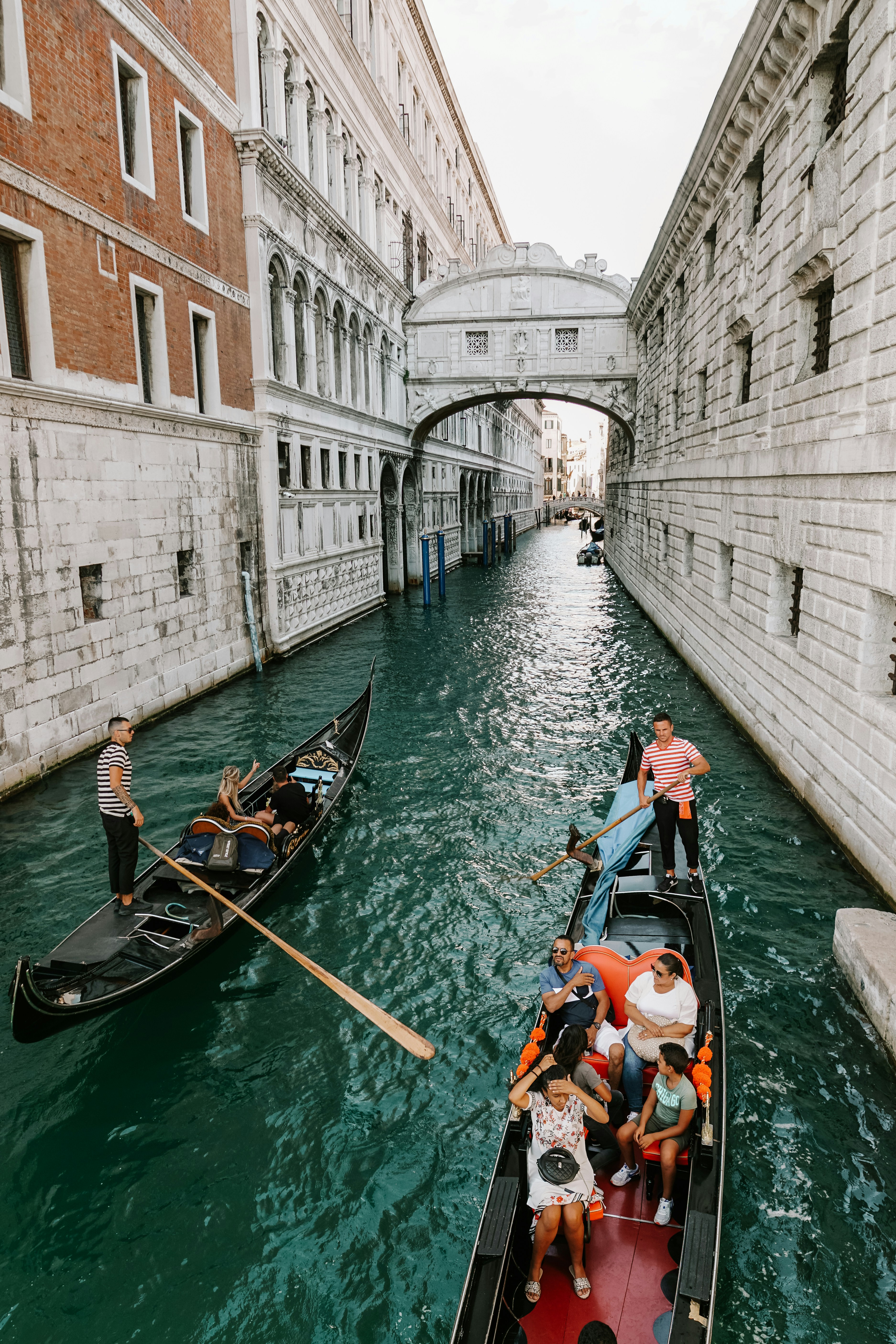 Two gondolas navigate the serene waters of a Venetian canal, framed by historic architecture. The scene captures the essence of leisurely exploration in Venice.