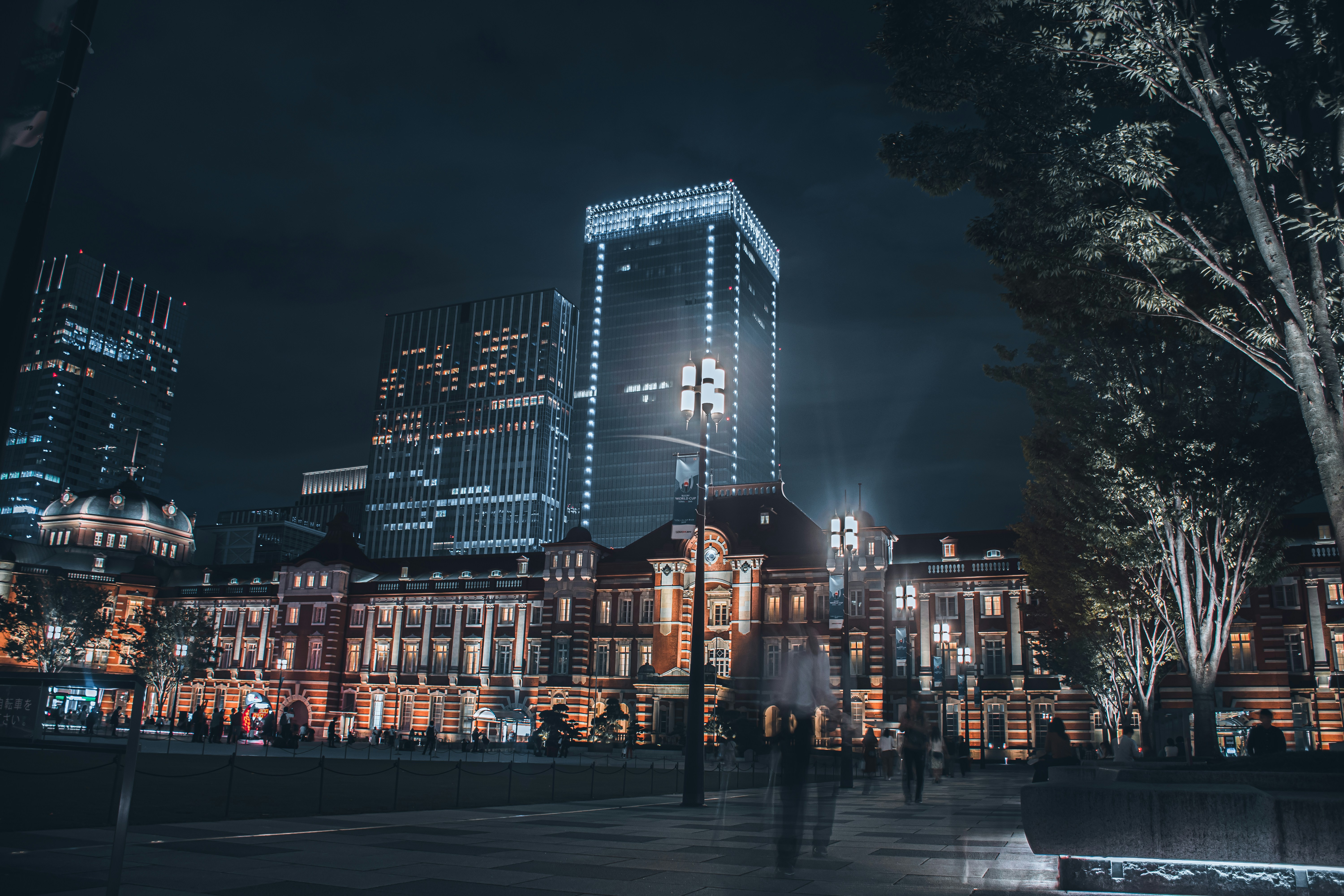 People walking on sidewalk near high rise buildings during night time ...